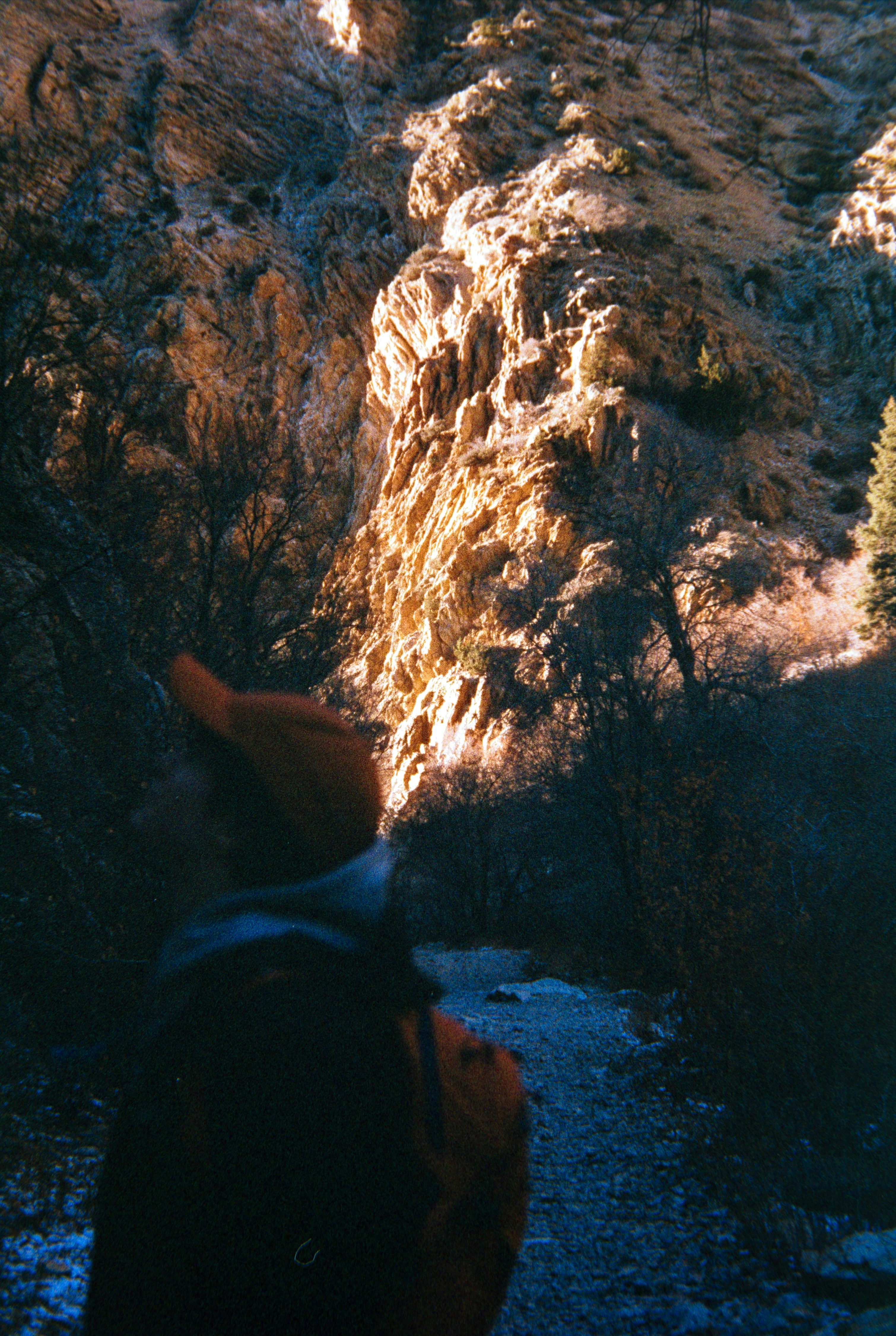 Dawn Trail: A Shrouded Figure Along a Rocky Corridor