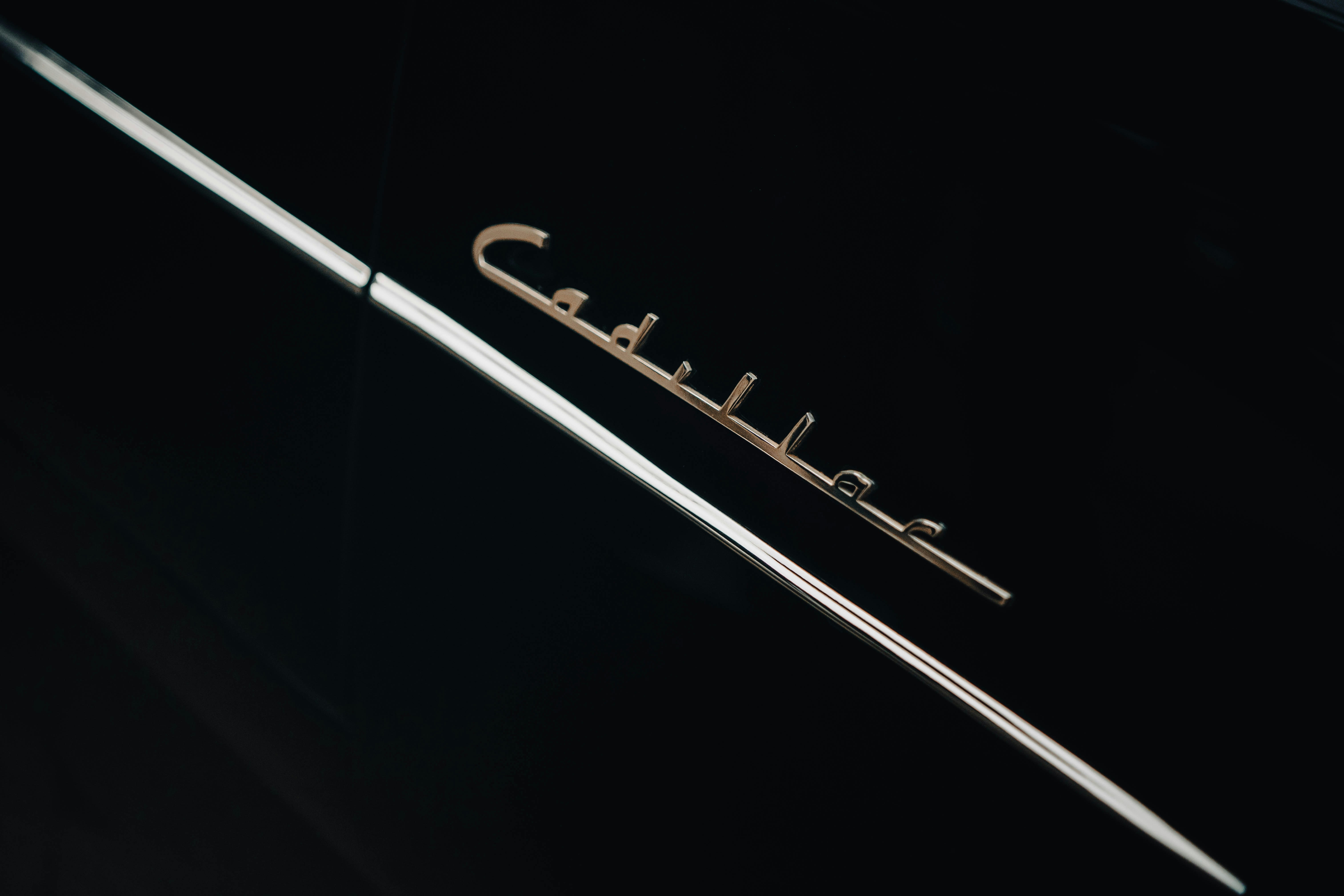 Chrome Script: The Cadillac Emblem Gliding Across a Midnight Panel