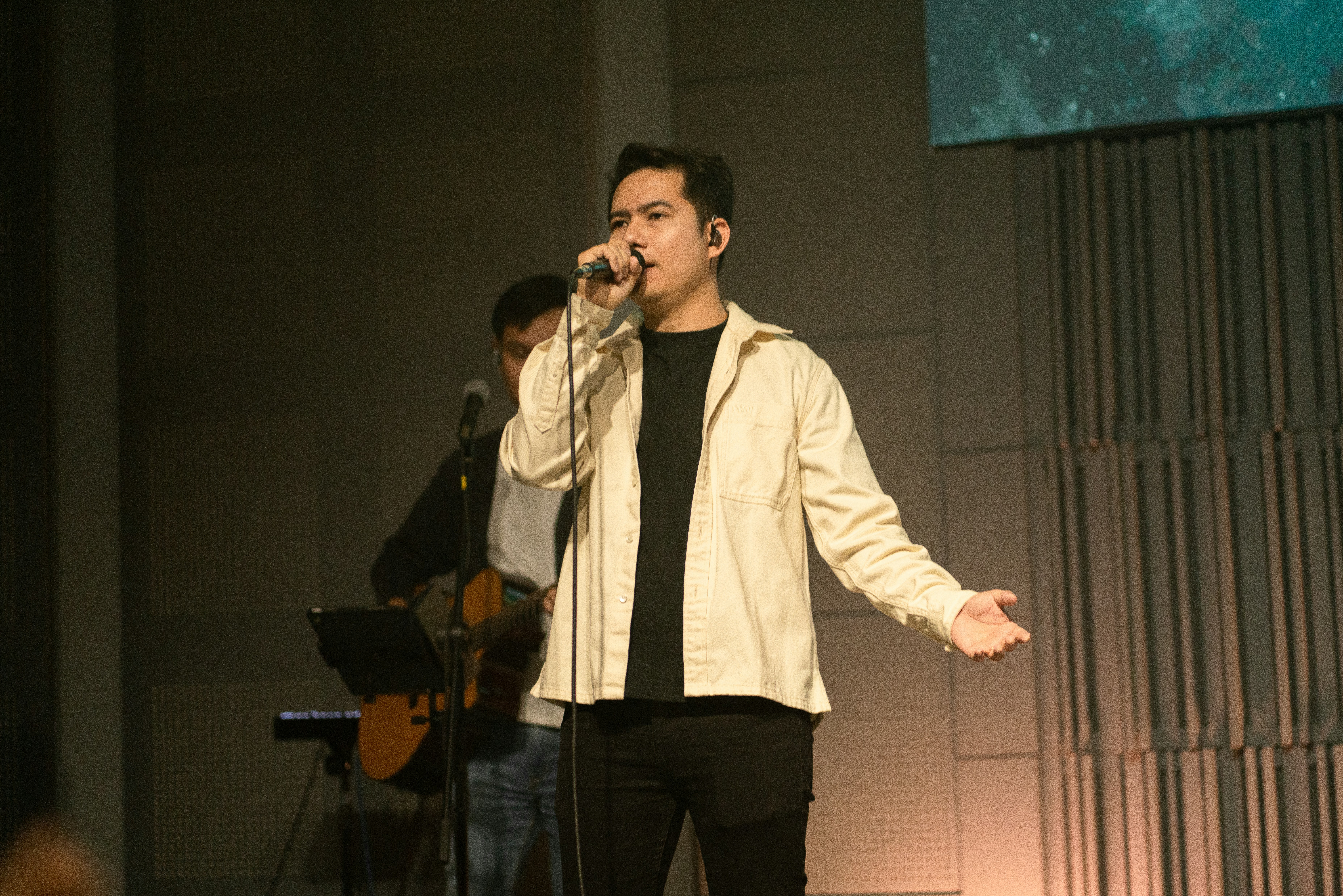 A man singing into a microphone on stage. photo – Free Art Image on ...