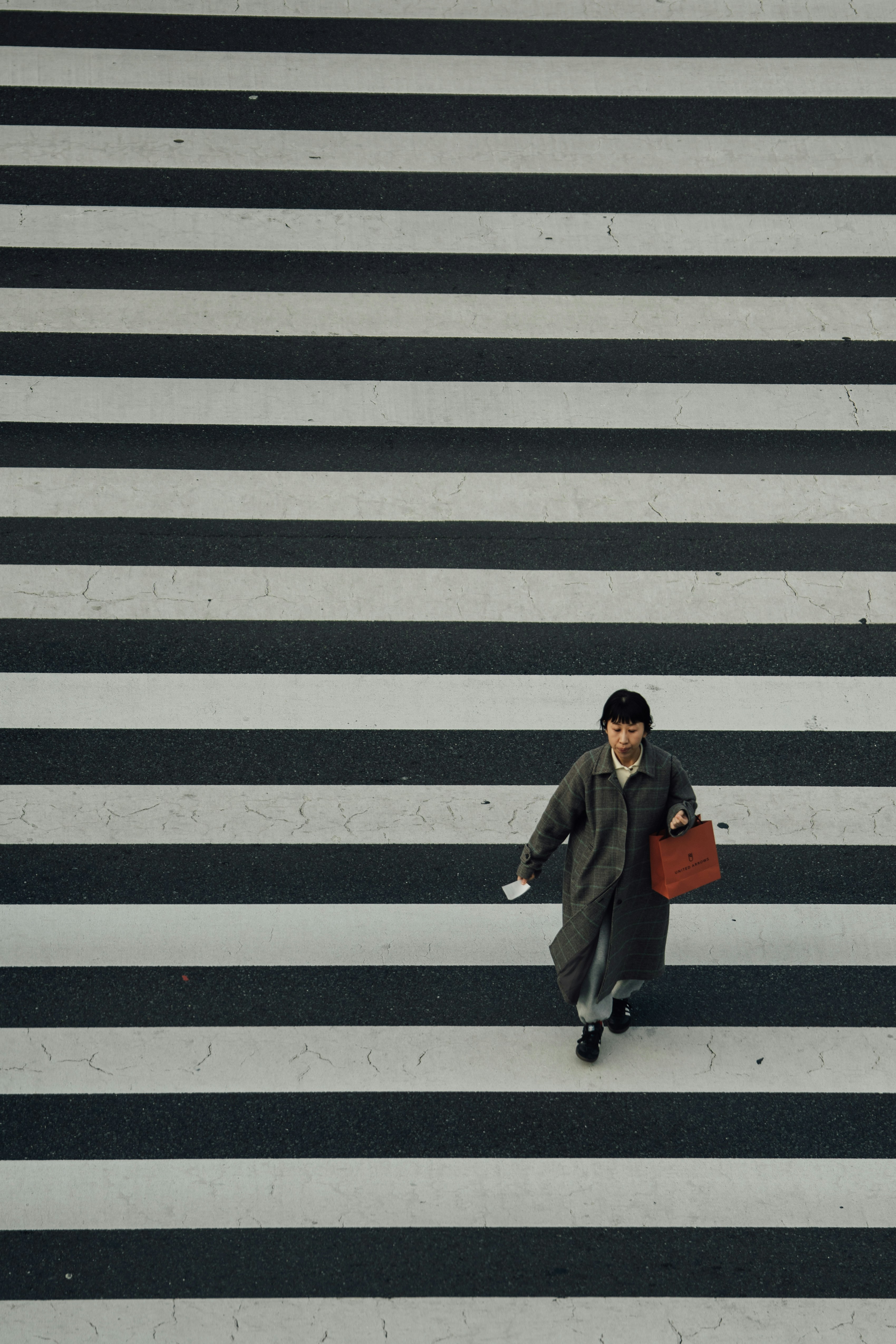 Crosswalk Ascent: A solitary figure strides across bold stripes