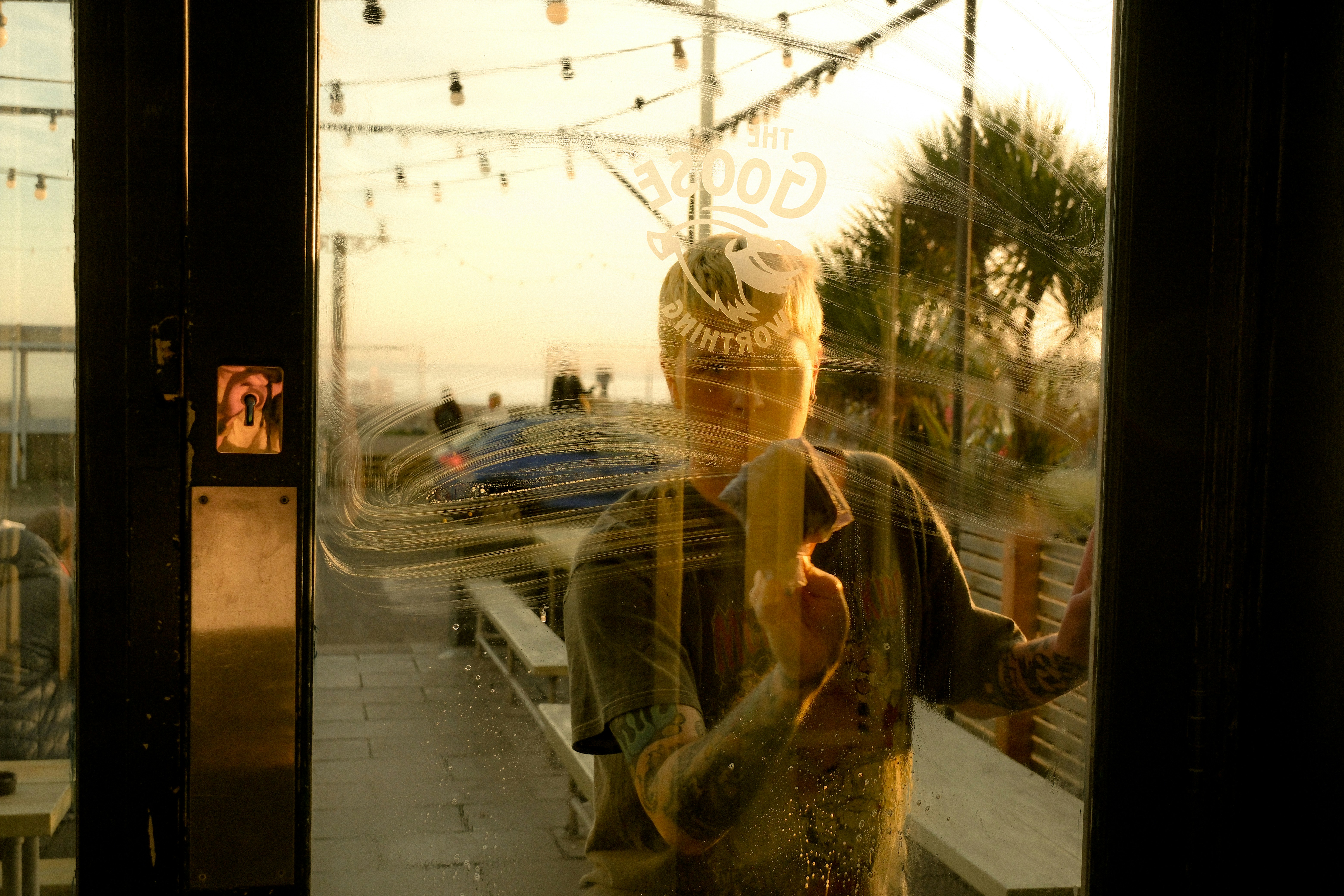 Man reflected in glass door looking out at beach.