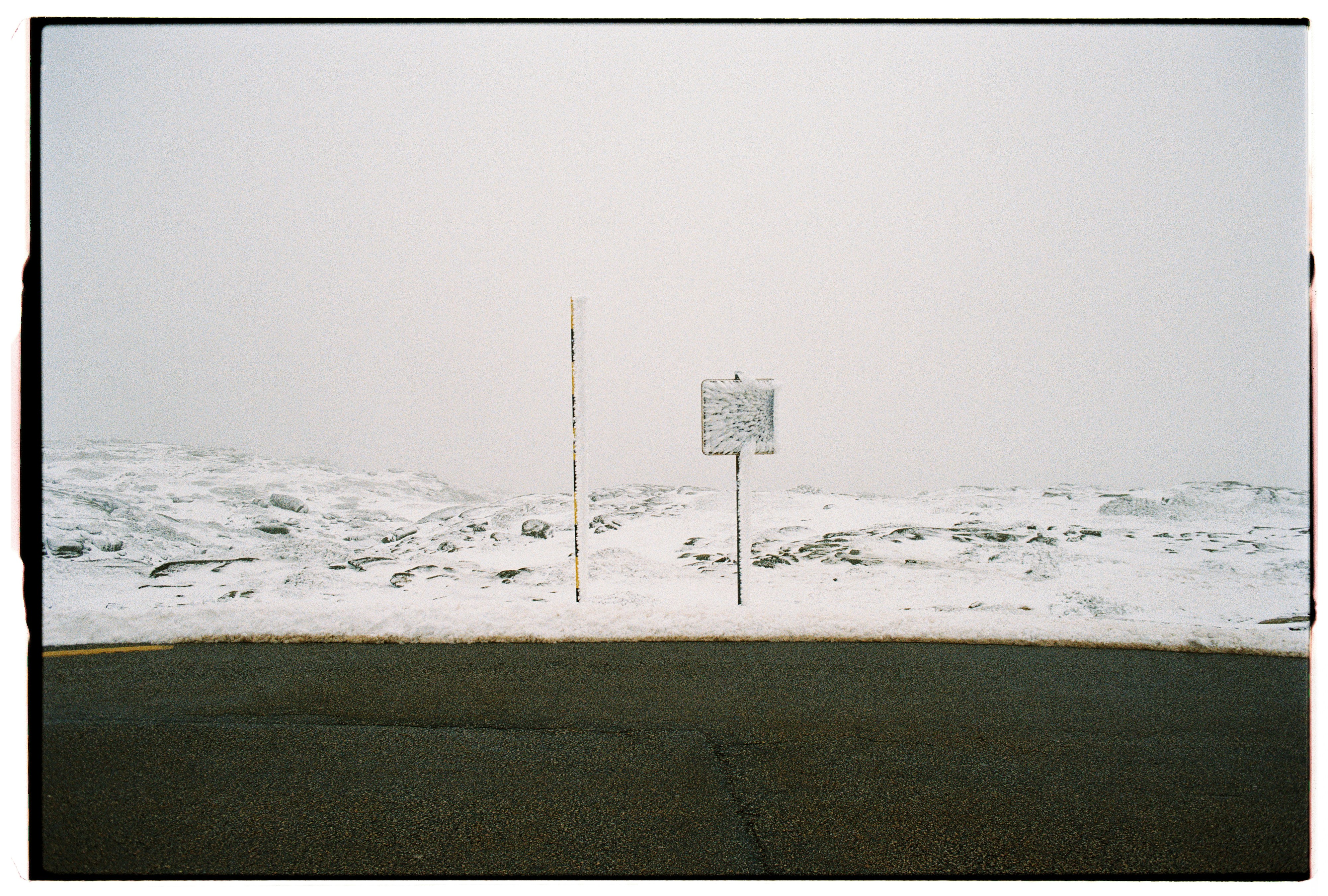 Snowline over Tarmac: Minimal Roadside Scene with Signage