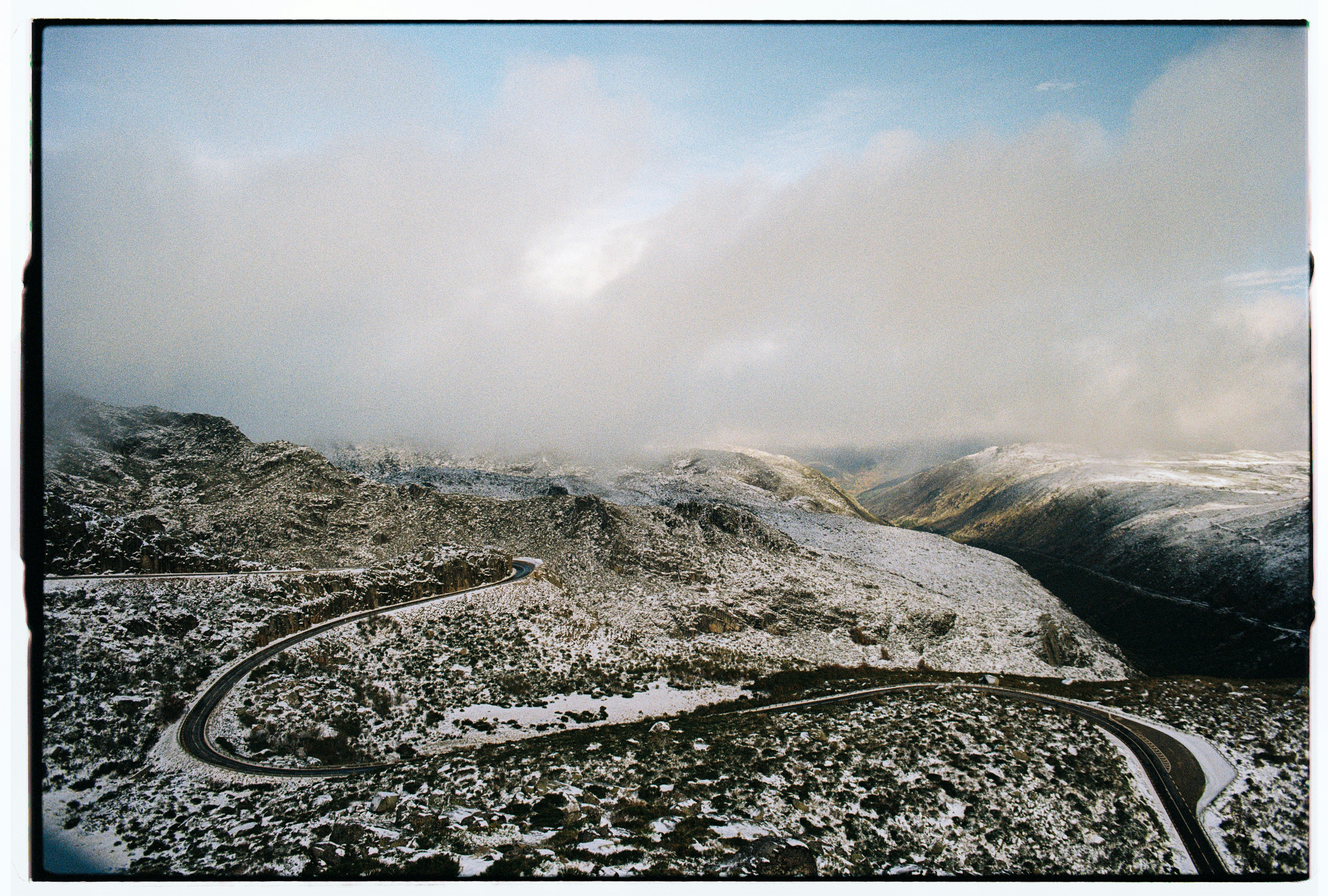 Winding Alpine Road Under a Quiet, Cloud-Washed Sky