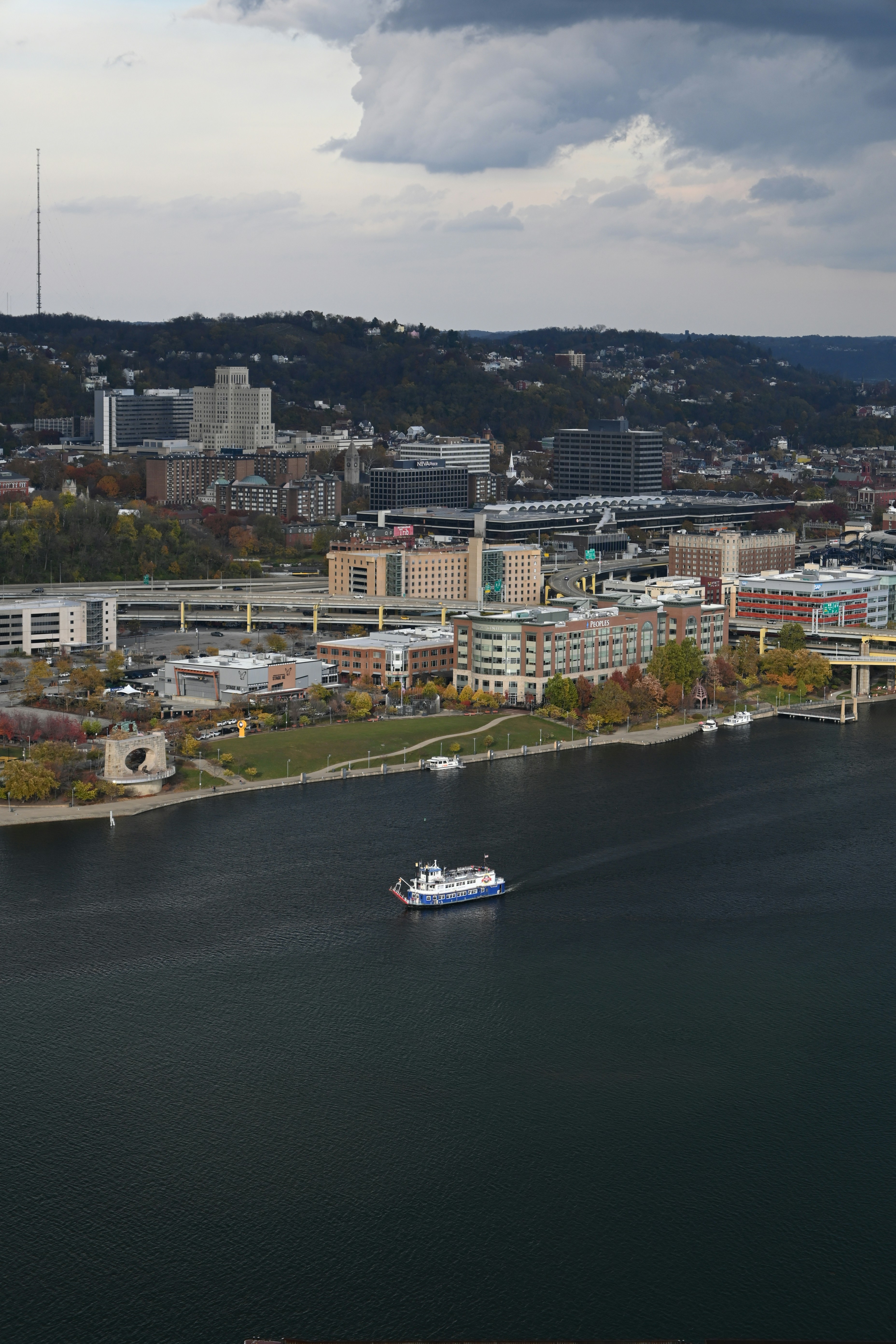Riverfront Cityscape with Ferry Beneath a Looming Cloud