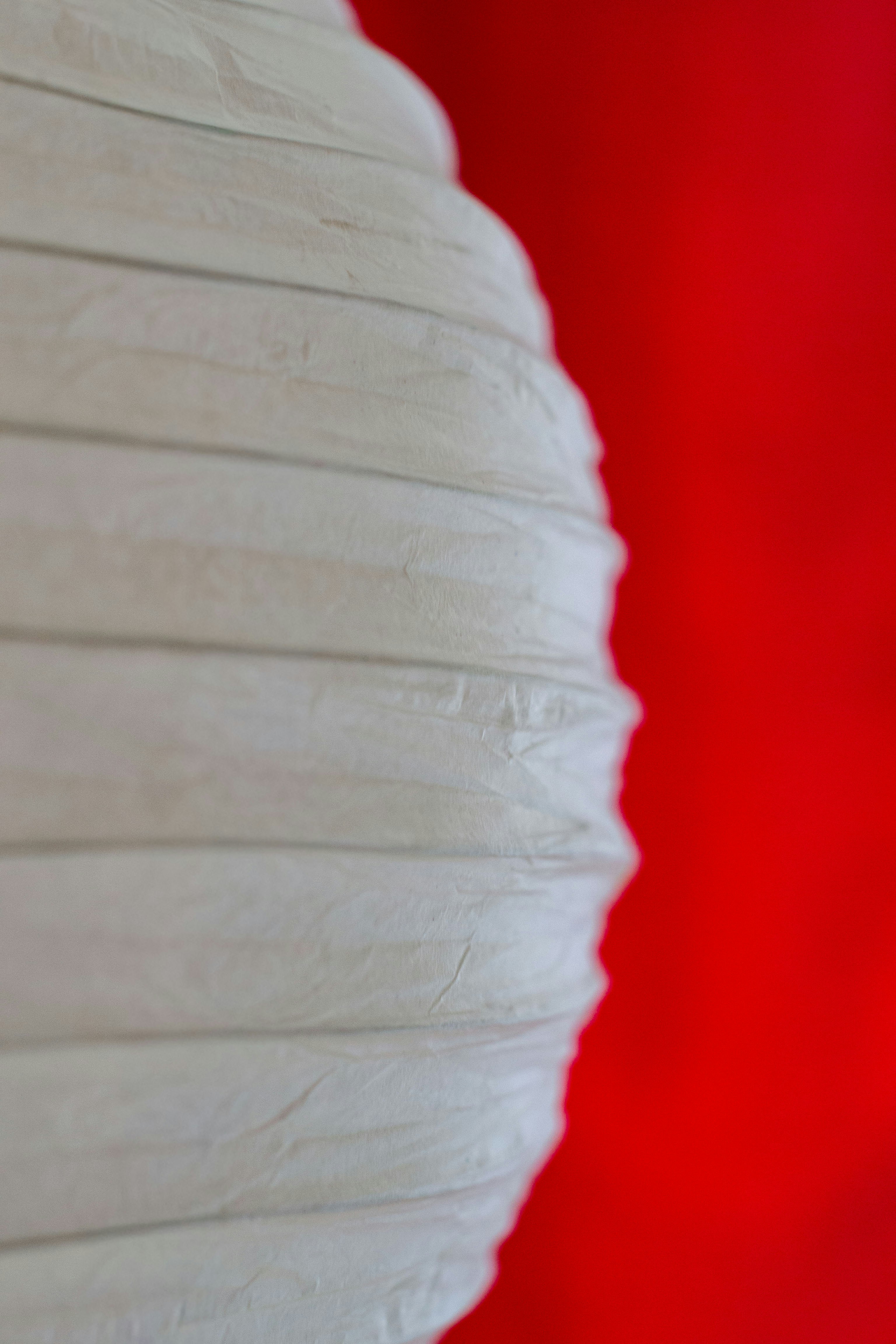Contrast of Texture: White Lantern Form Against Fiery Red Backdrop