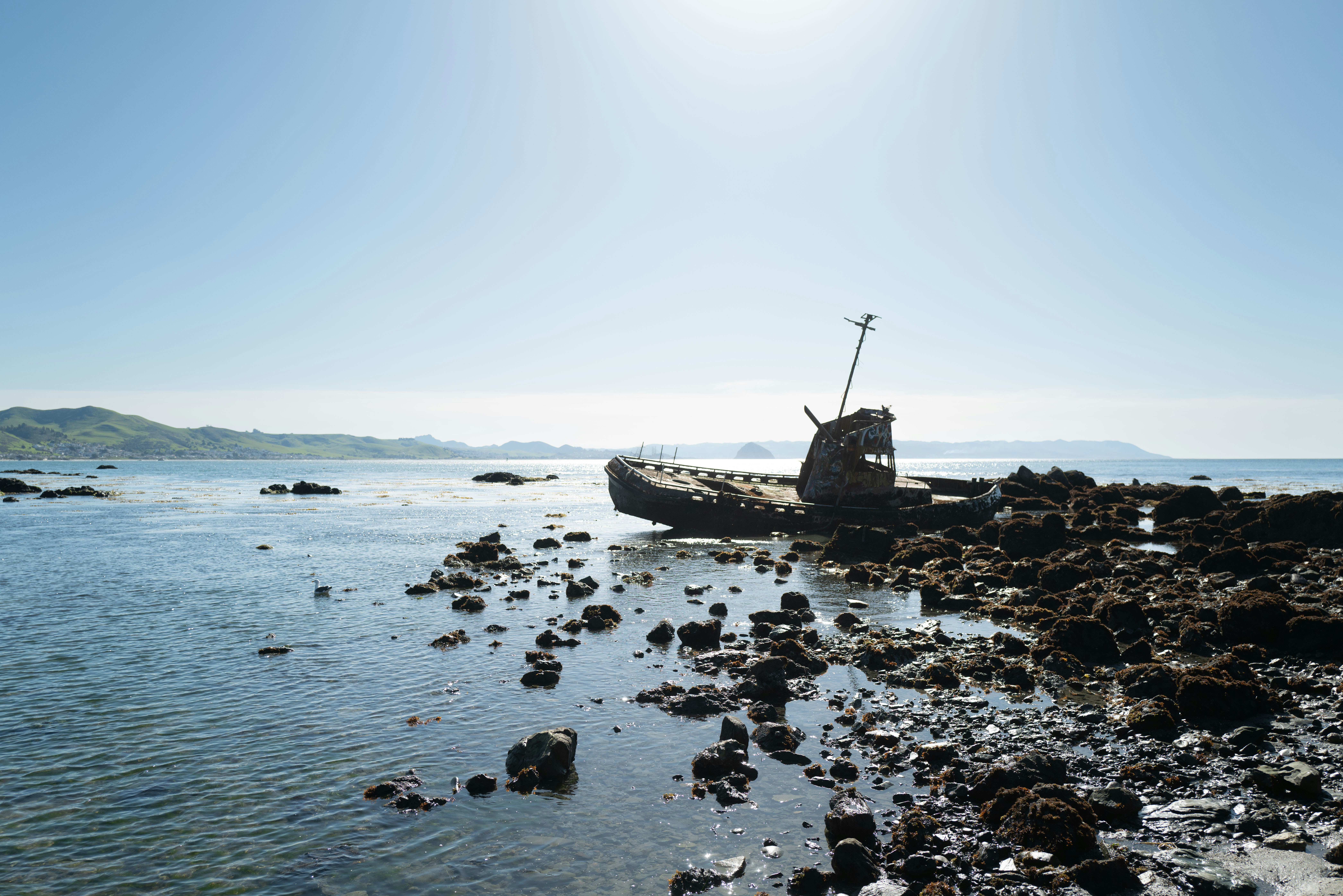 Sunlit Wreck Resting Among Tidal Rocks at the Quiet Shore