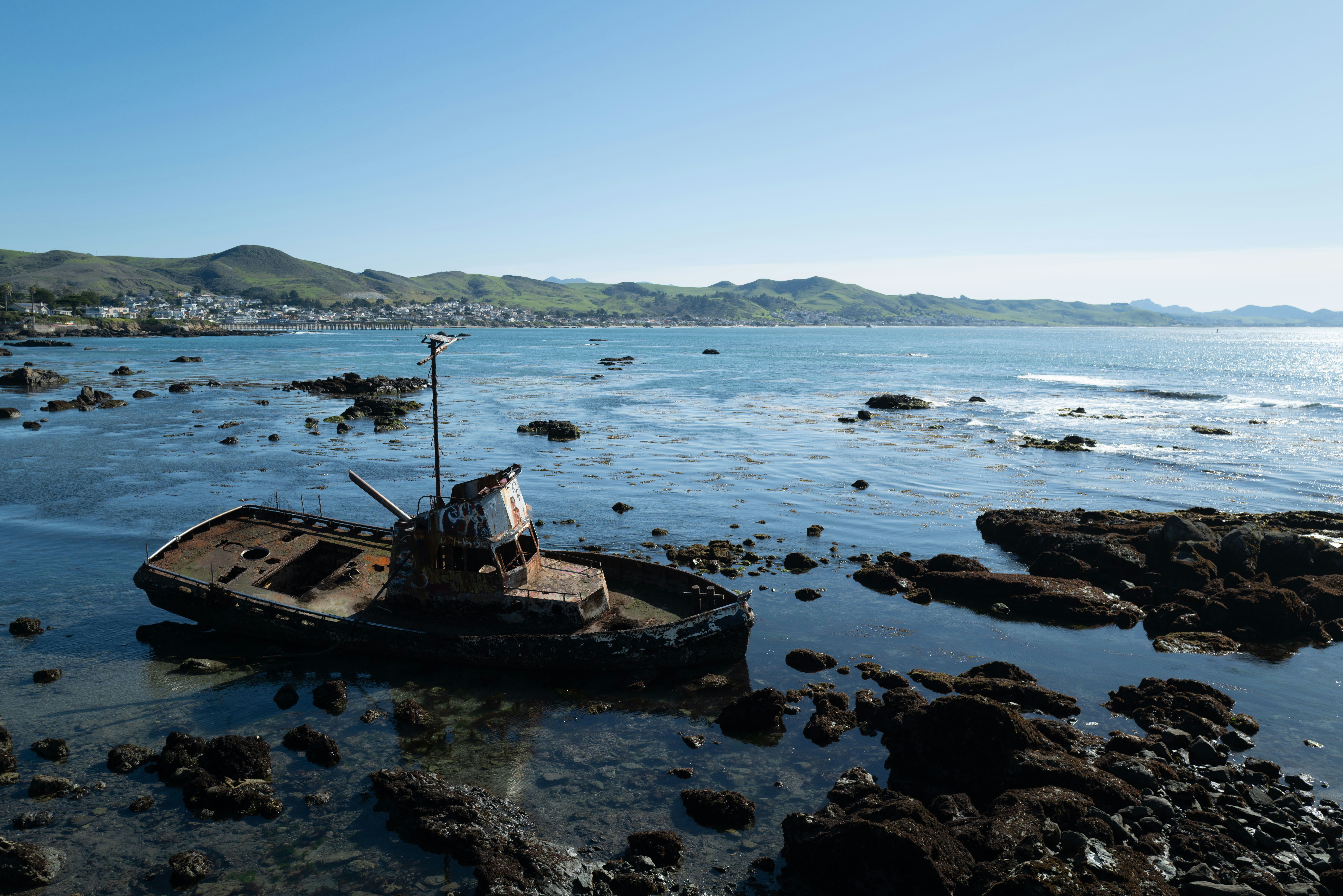 Deserted hull in tidal blue: a rusted survivor in a rocky shoreline