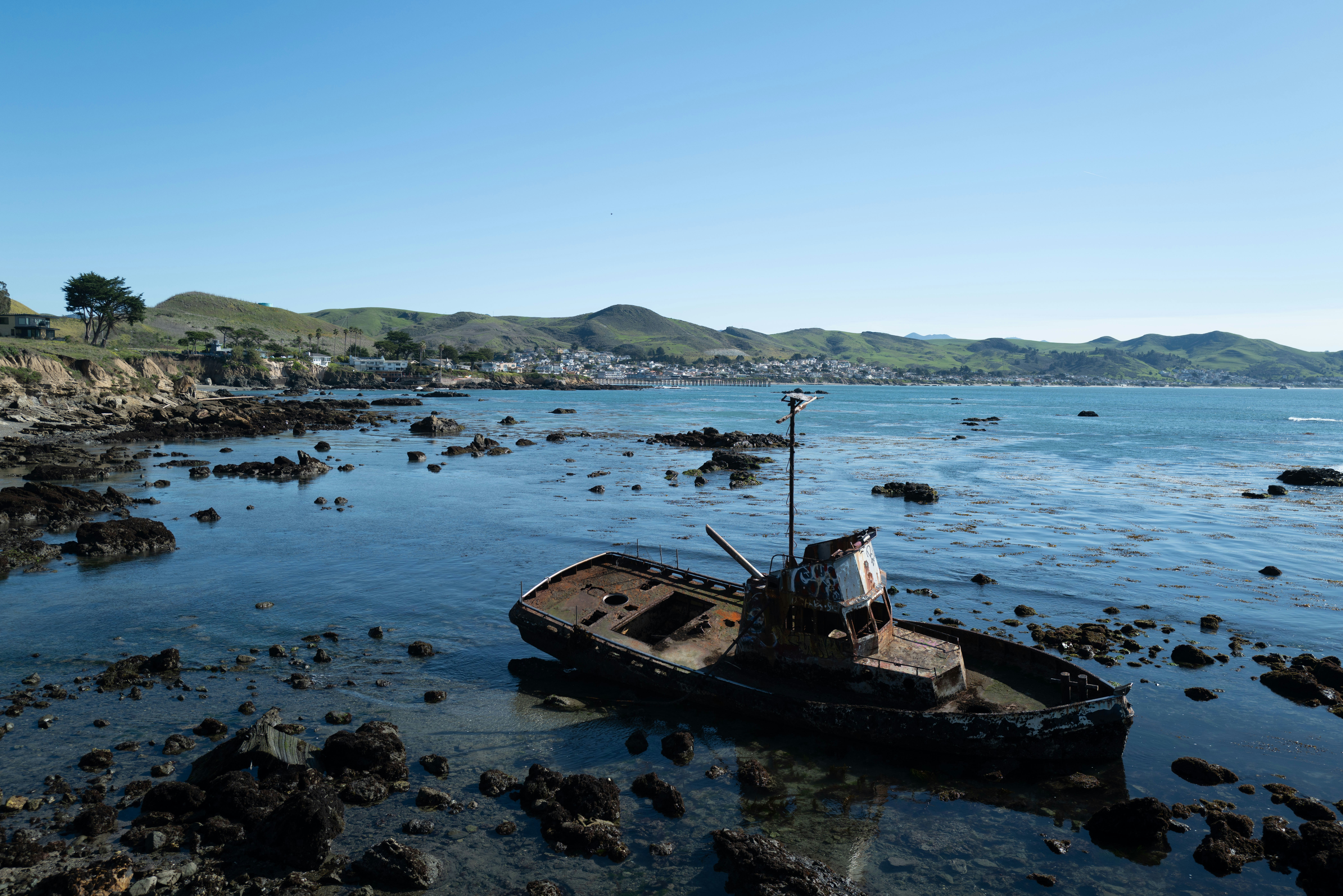 Sunken Workhorse at Low Tide: A Distant Coastal Village and a Rusted Boat