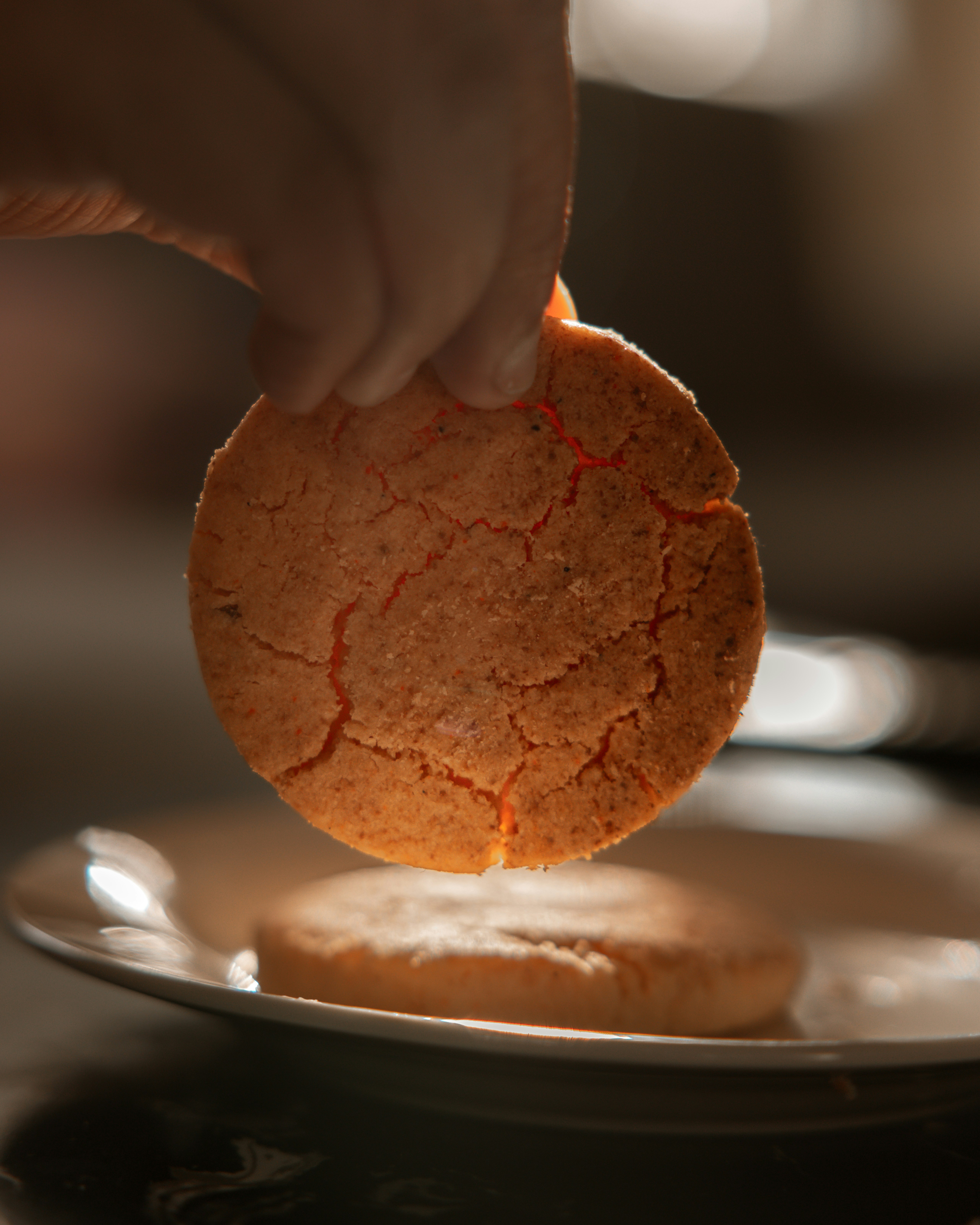 Crackled sugar cookie being placed onto a plate, close-up with warm kitchen lighting