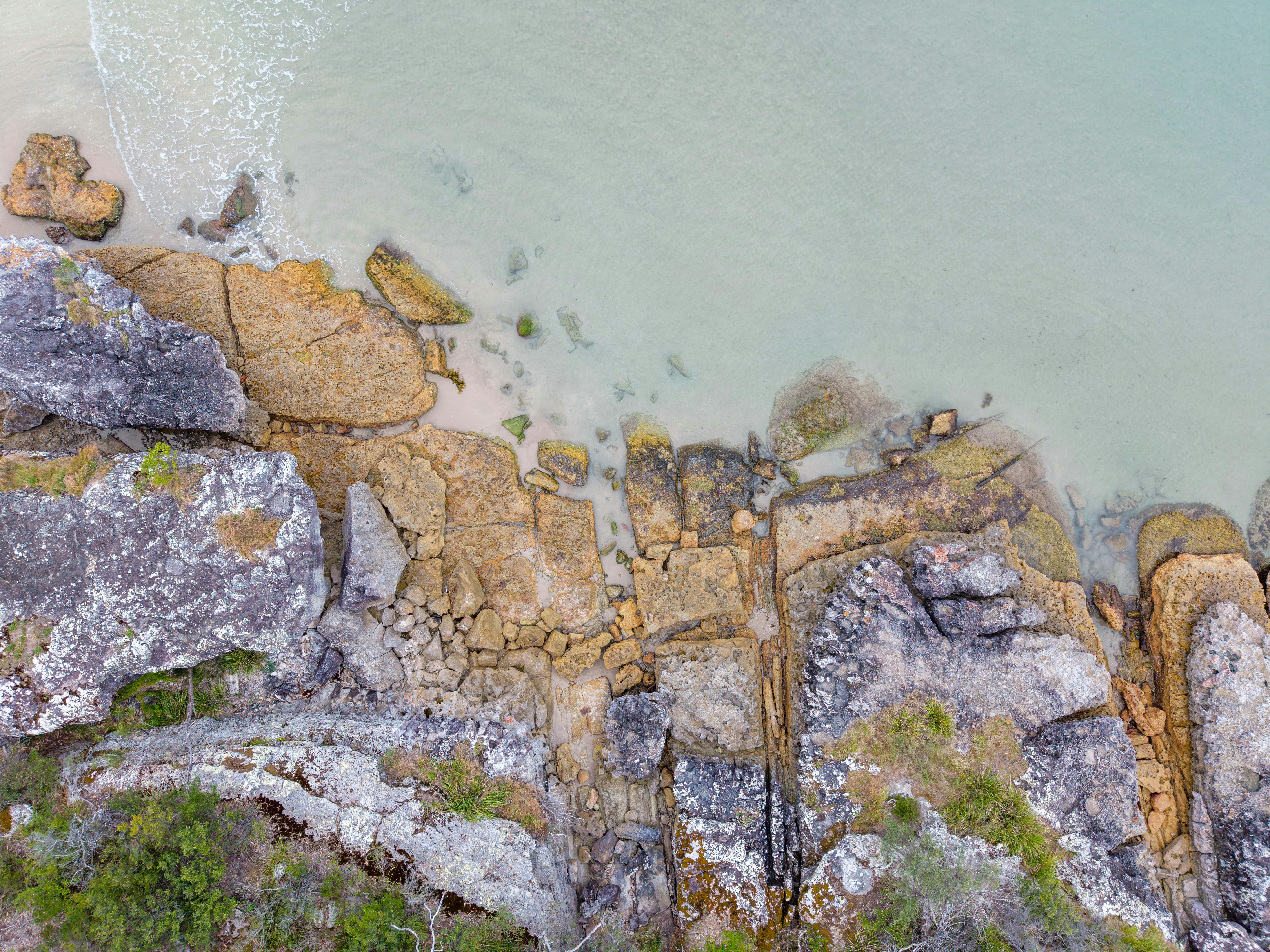 Craggy shoreline mosaic: weathered rocks meeting turquoise tide