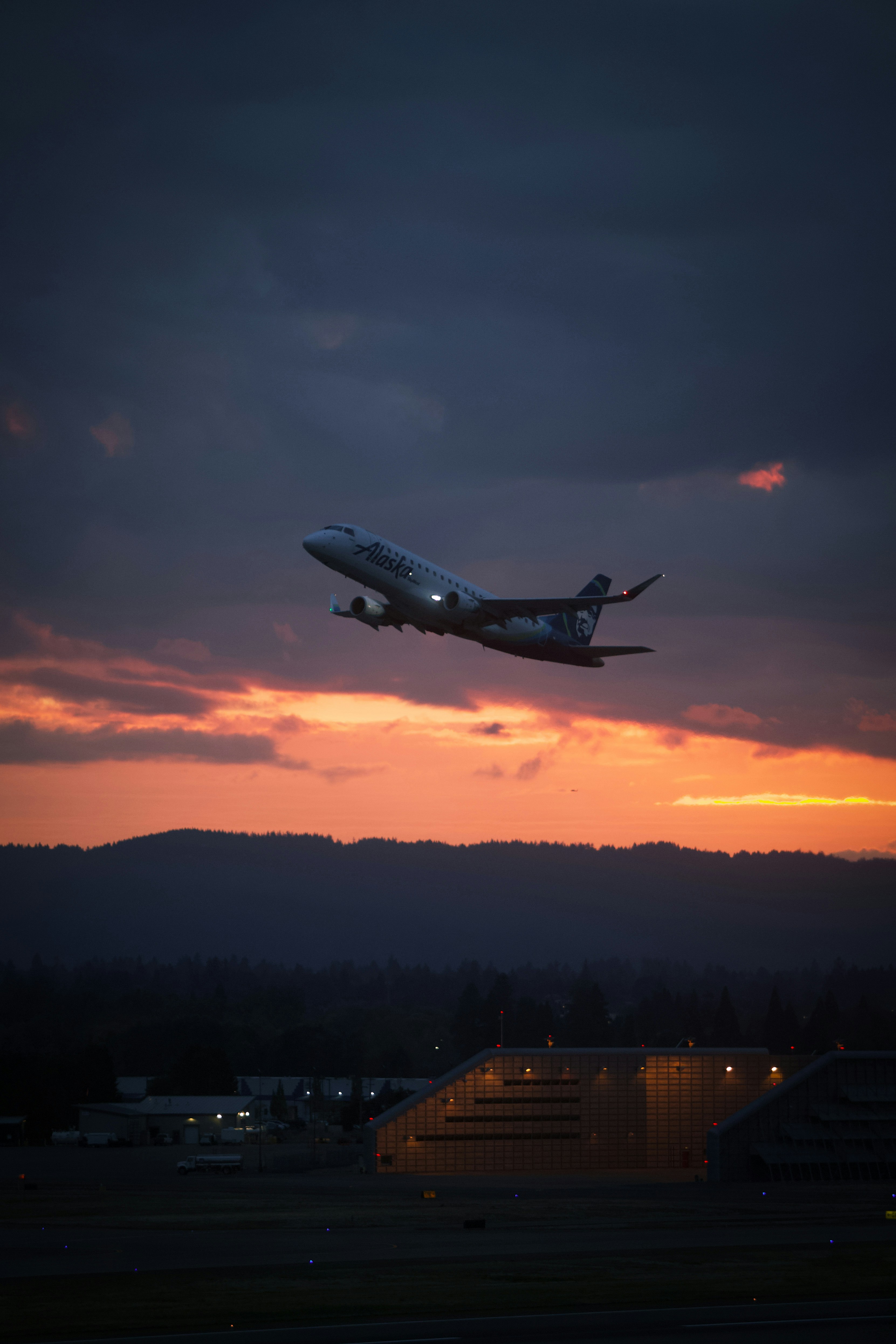 Sunset ascent: a lone Alaska Airlines jet climbs above a glowing horizon