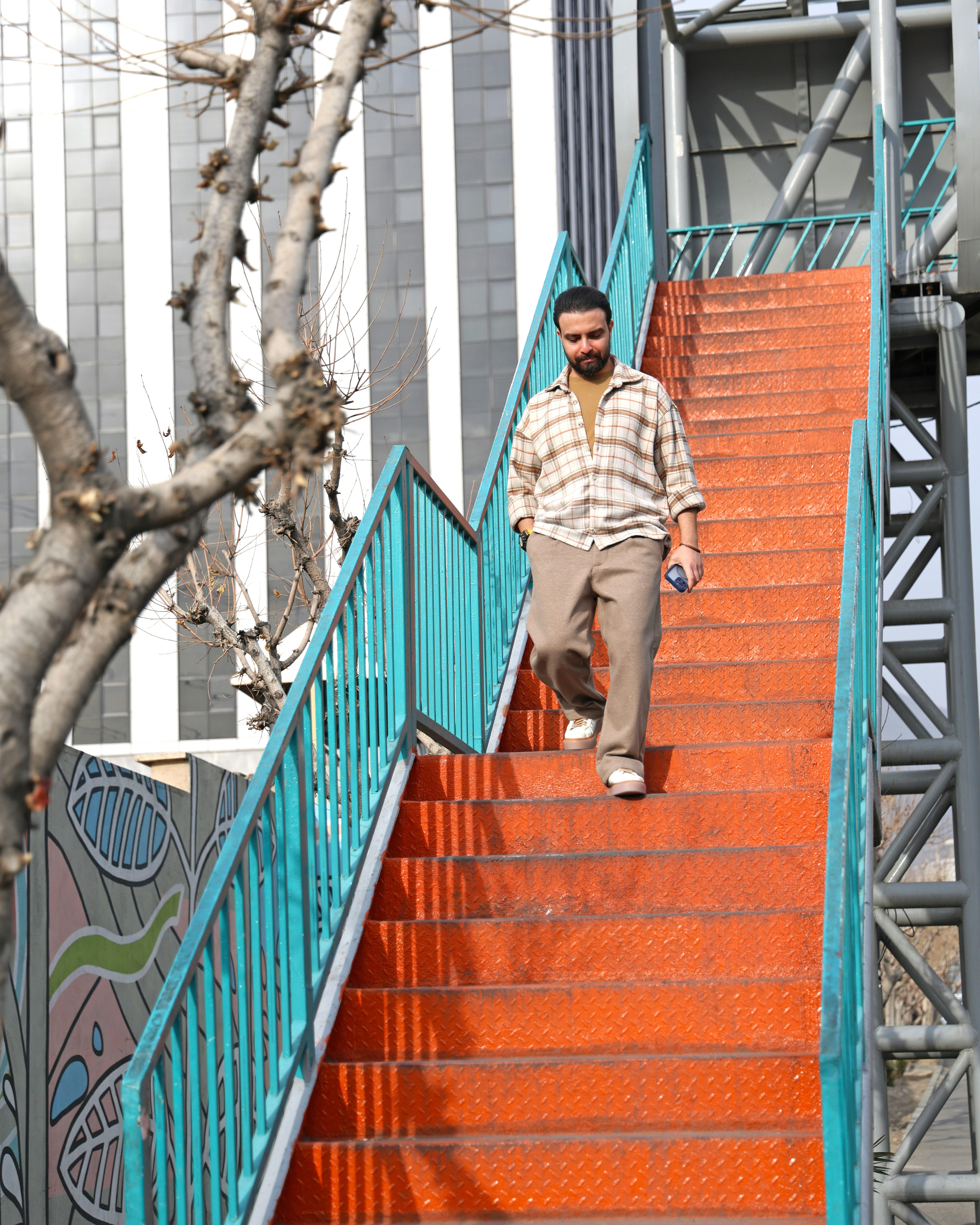Man Descends a Vibrant Orange Staircase Under a Modern Urban Canopy