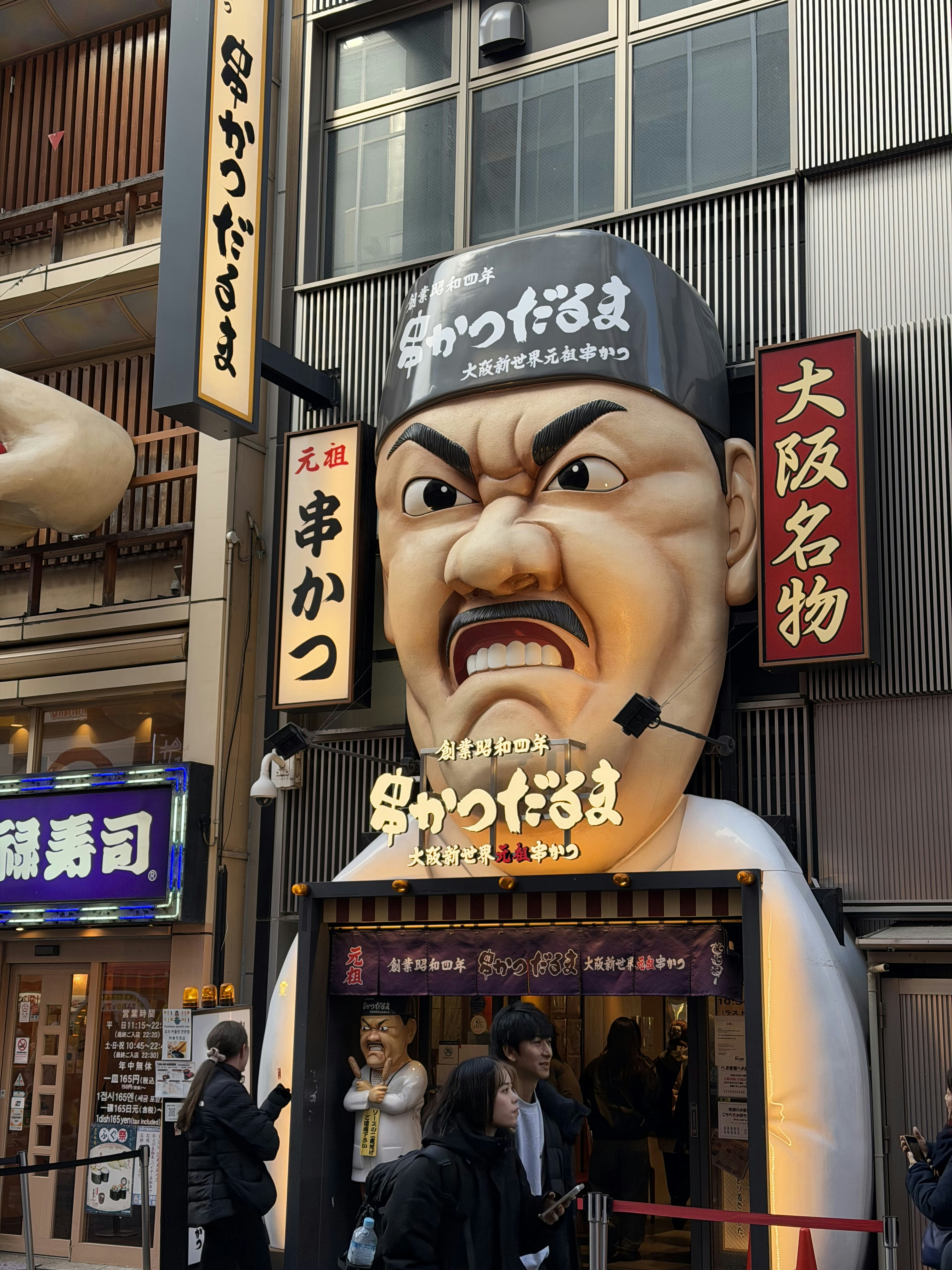 Giant Boss Face Above the Entrance in a Busy Osaka Street