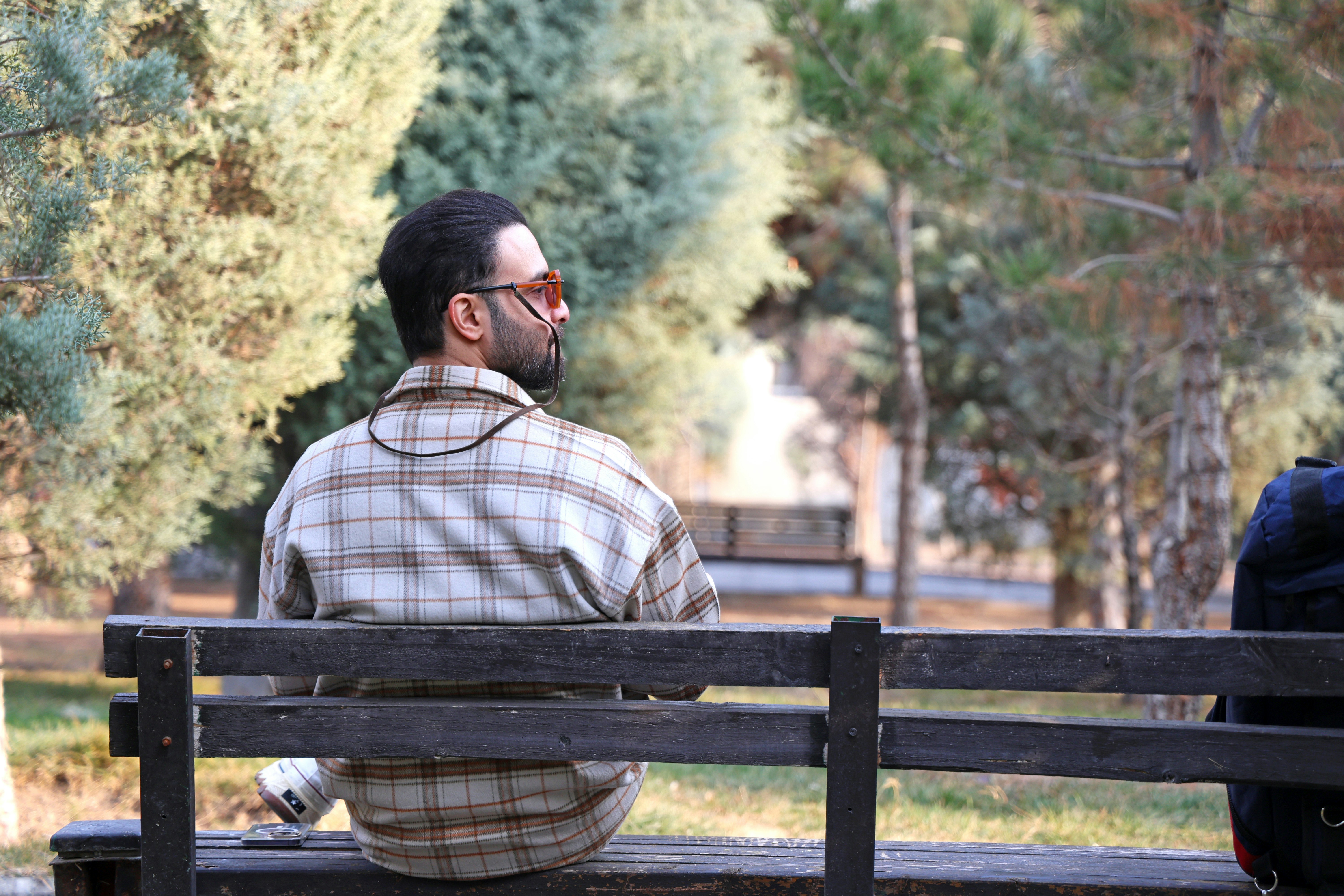 Quiet Moment on a Park Bench: A Man in Plaid Embraces the Afternoon