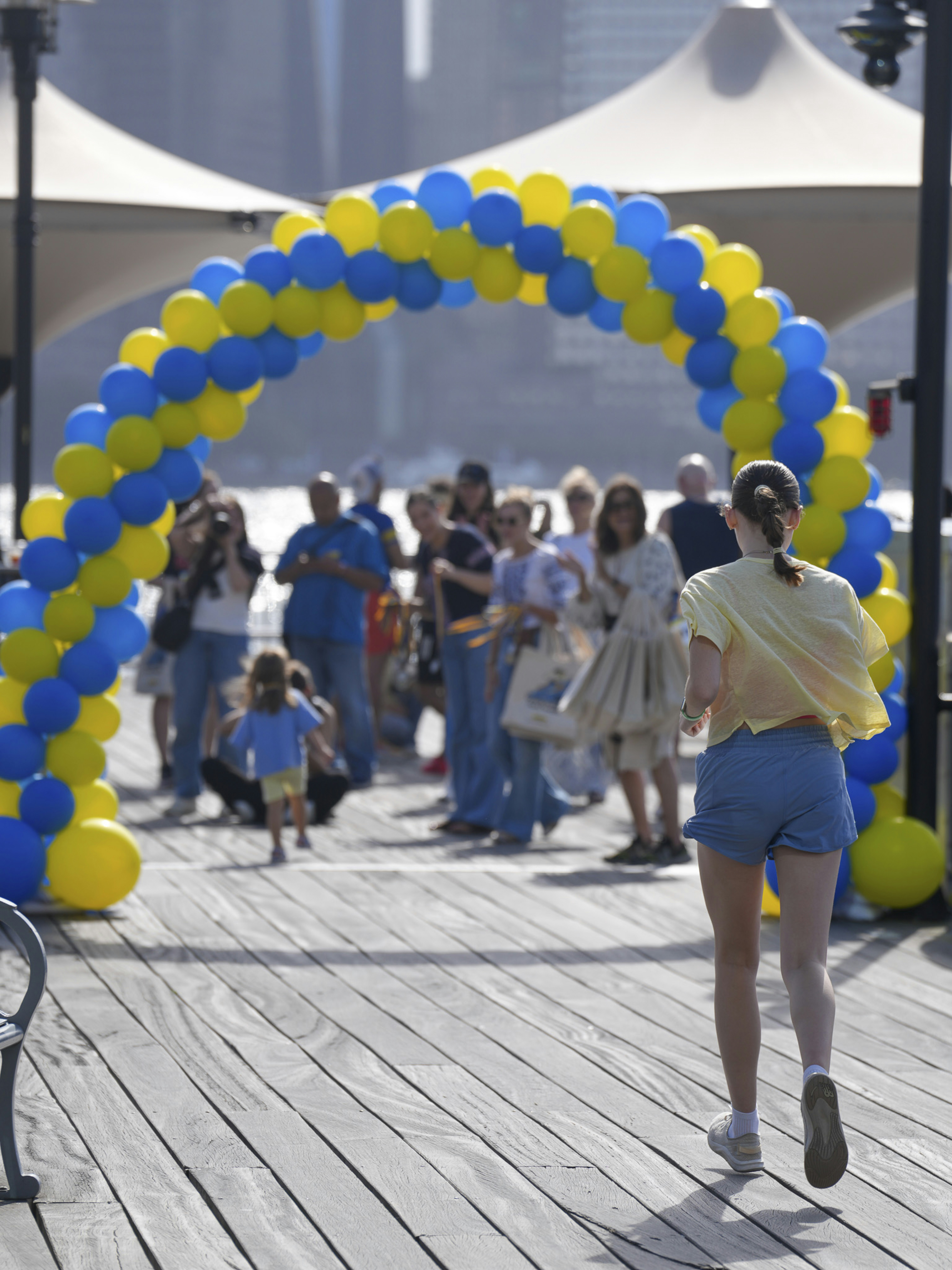 By Oleksandr Buzunov. Instagram: @buzunov.photoart A community comes together on the Jersey City waterfront for the Vyshyvanka Run, a cultural charity race celebrating Ukrainian heritage, unity, and resilience. Runners cross the finish line wearing traditional embroidered vyshyvankas alongside modern athletic gear, symbolizing the connection between history and contemporary life. Blue and yellow medals mark moments of pride, relief, and shared emotion. These candid moments capture how Ukrainian traditions live on within the diaspora, carried forward through movement, community.