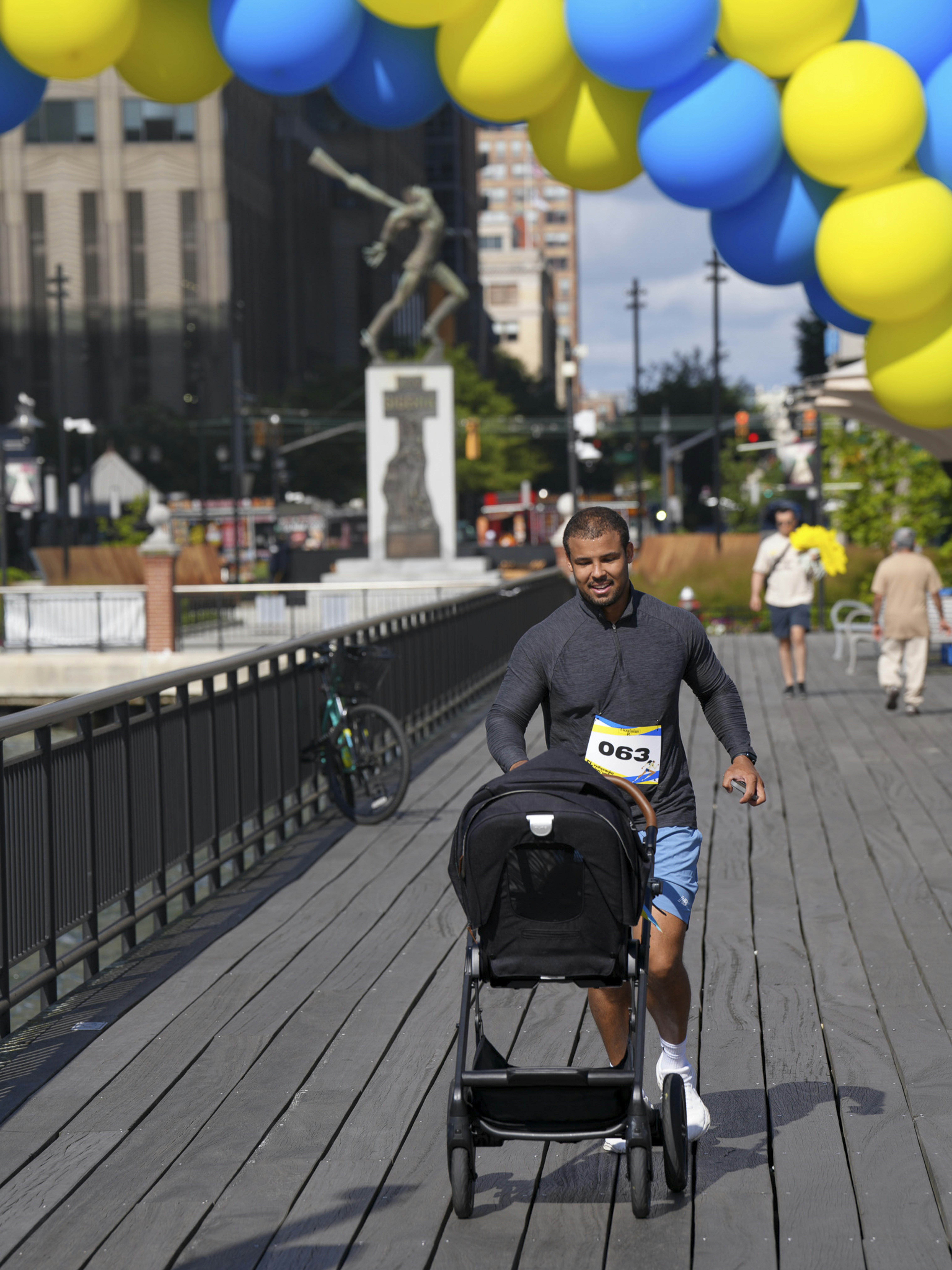 City Run: A Runner with a Stroller Under a Balloon Arch