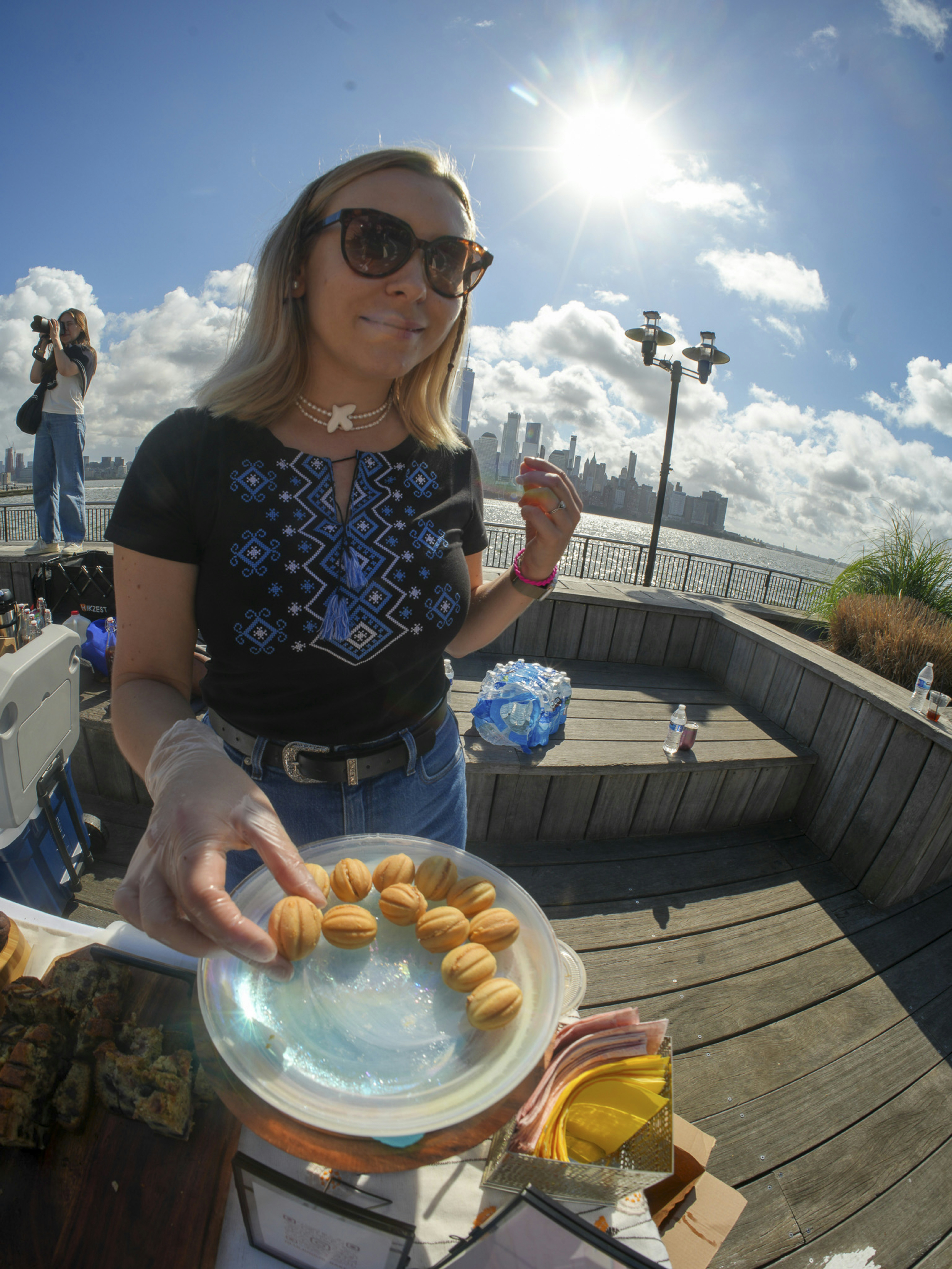 Sunlit plaza portrait with a playful pastry moment by the river