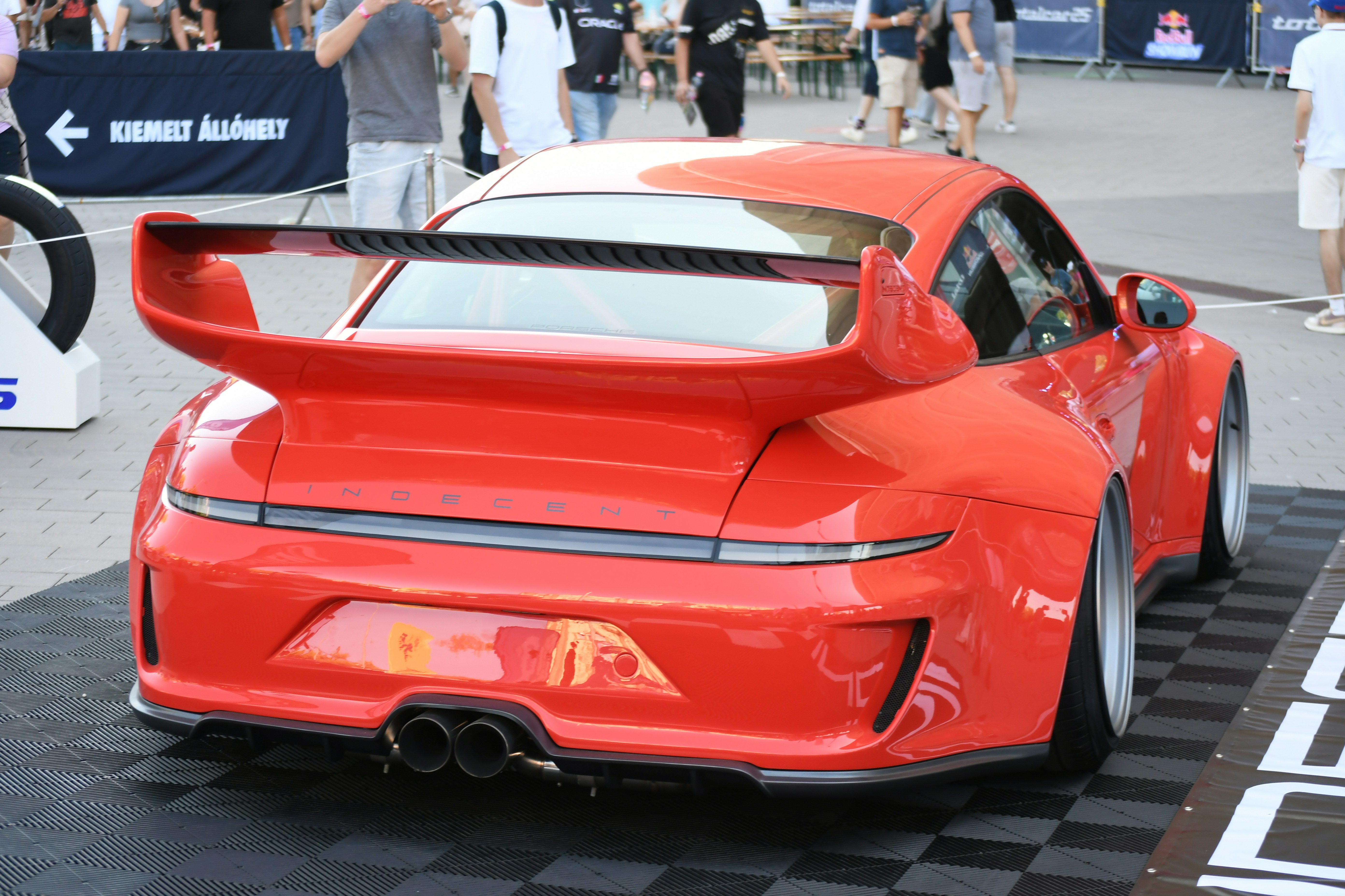 Rear-View Flame: A Scarlet Sports Car at a Public Show