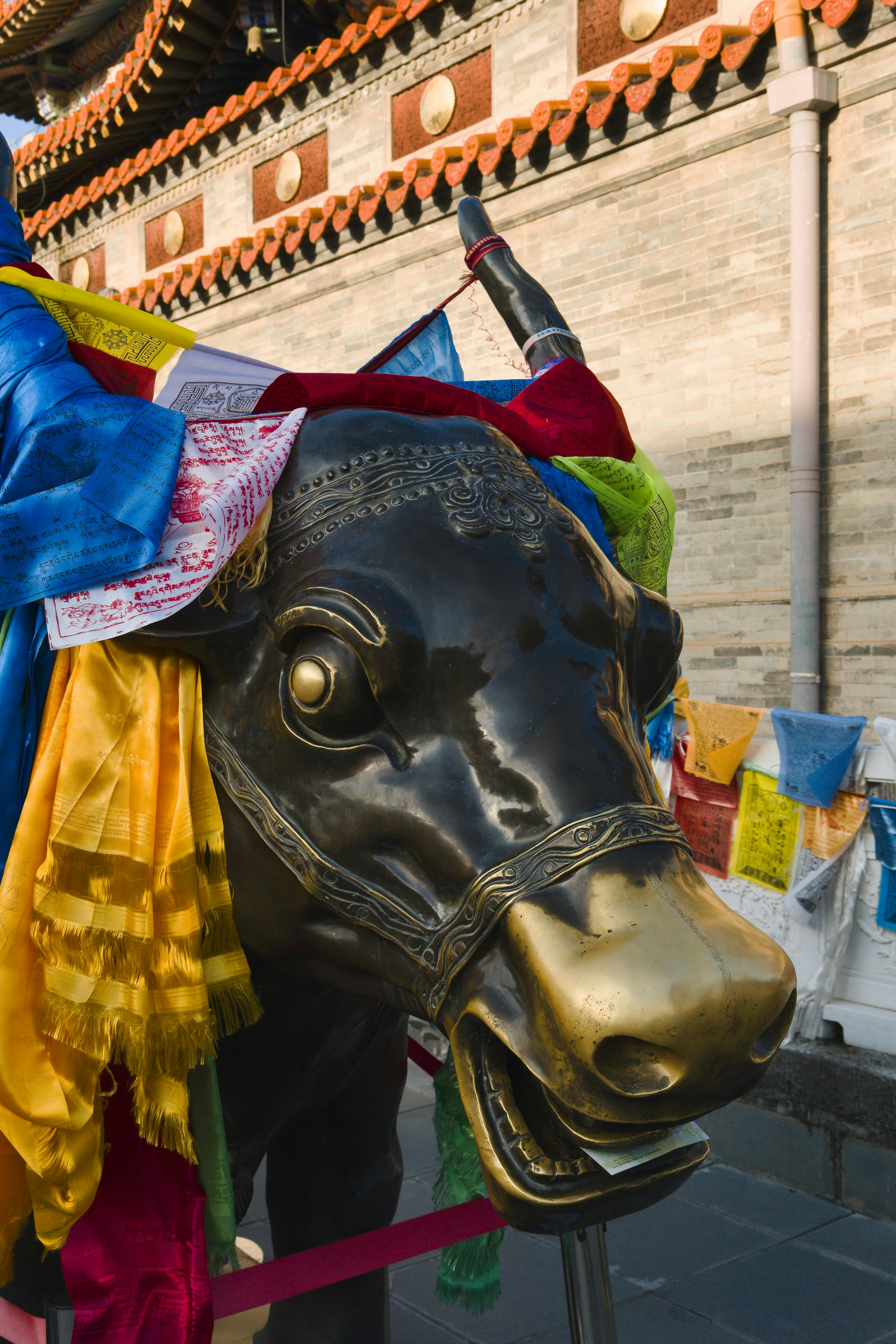 Colorful Prayer Flags Draped Over a Brass Ox Statue at a Temple