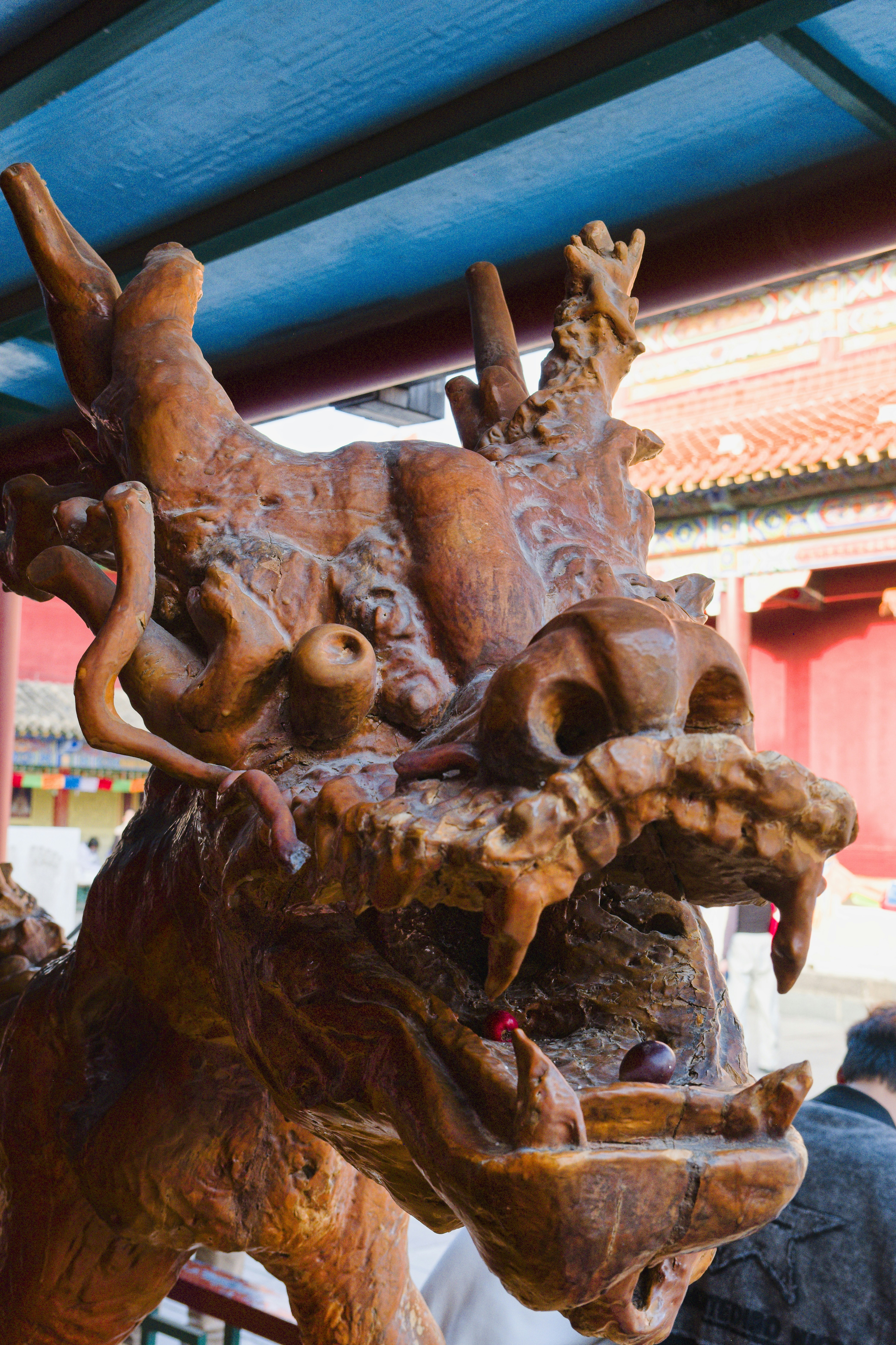 Bronze Dragon Guardian: A Busting Carved Head Emerges Under a Colorful Roof