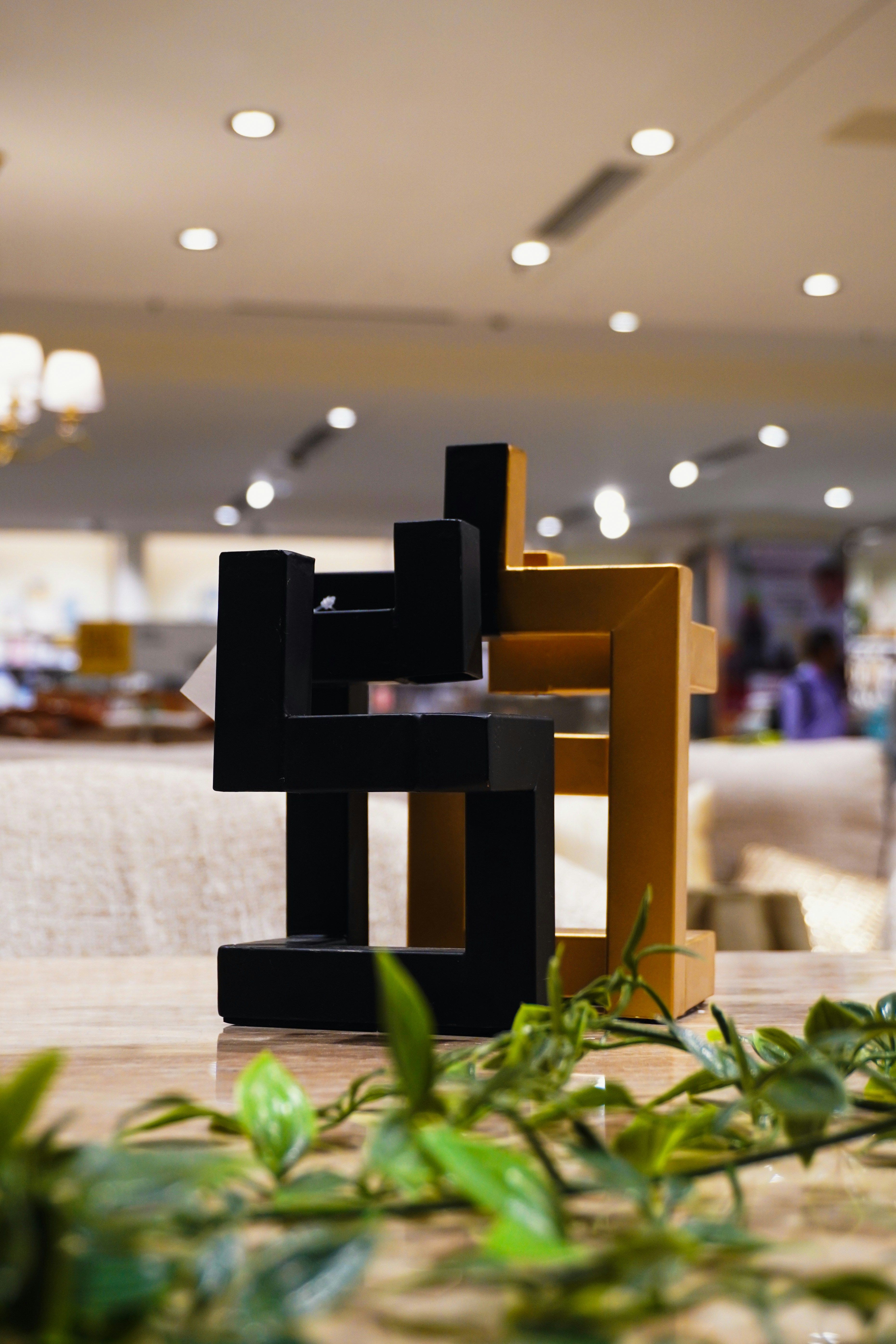 Interlocking Monoliths: Black and Gold Puzzle Structures on a Plant-Filled Table