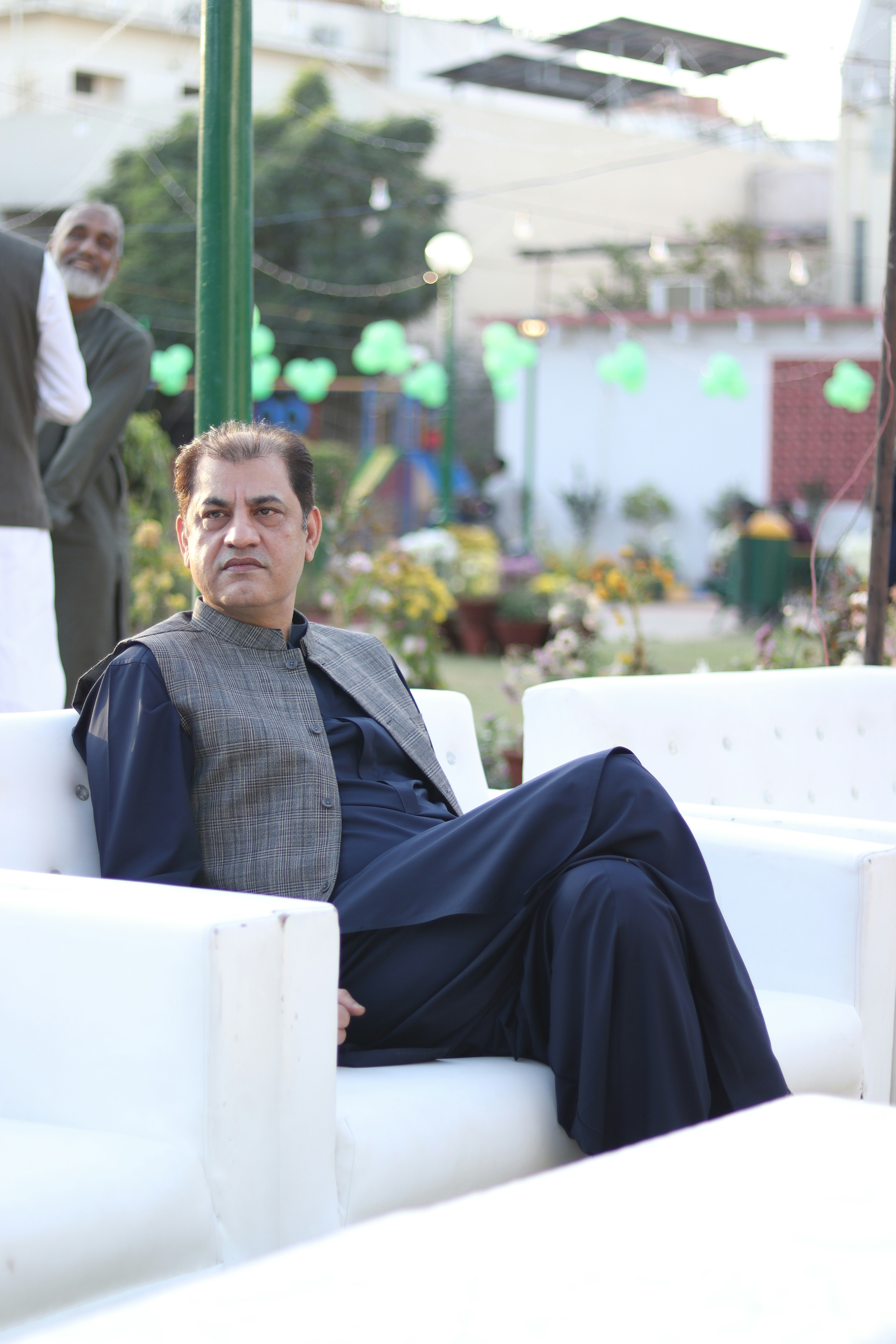 Quiet Authority: the seated man in traditional attire watches the scene unfold