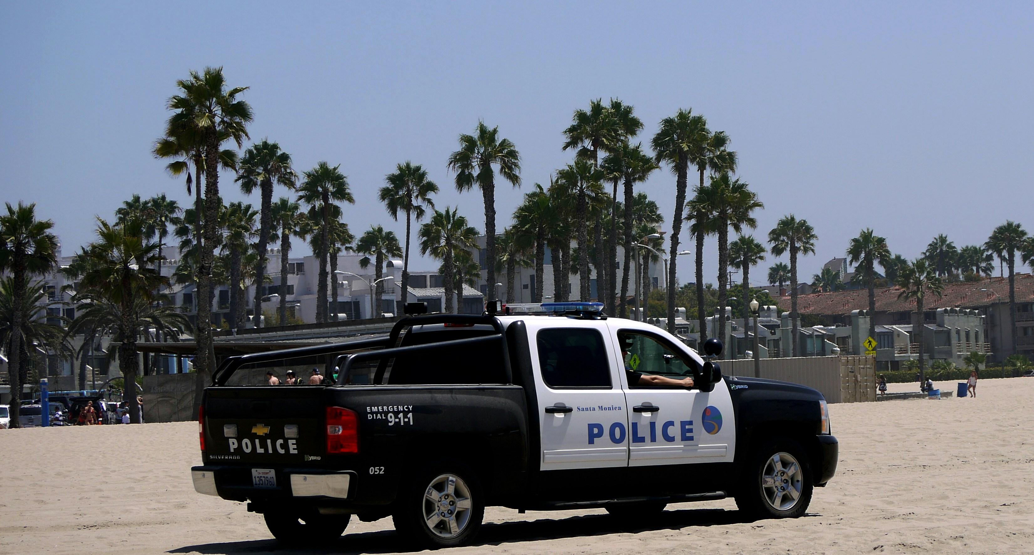 A police van on the sand at Santa Monica beach with palm trees on background