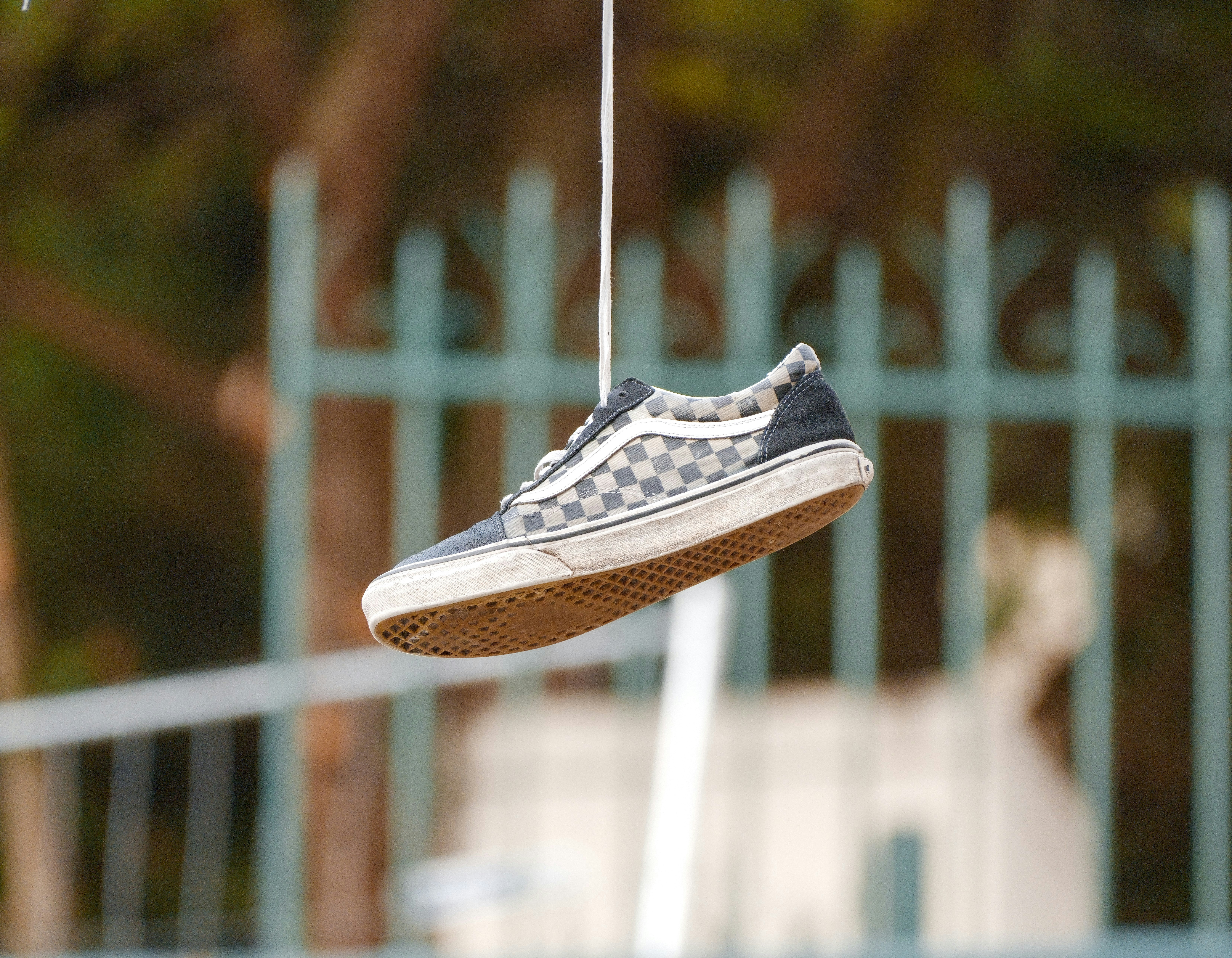 Airborne Slip: A Well-Worn Checkerboard Shoe Suspended Above the Ground