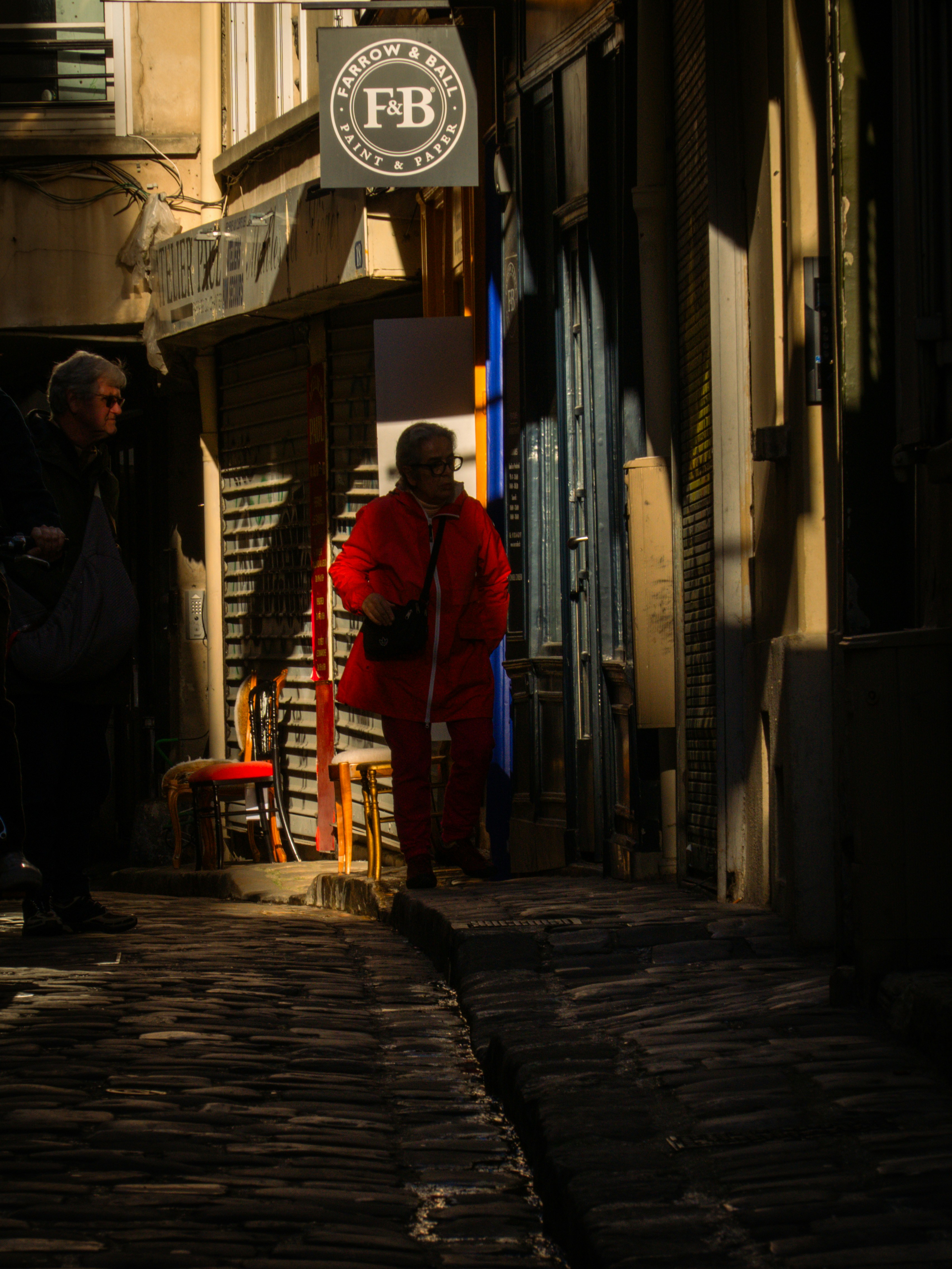 Red‑clad wanderer in a narrow sunlit alley