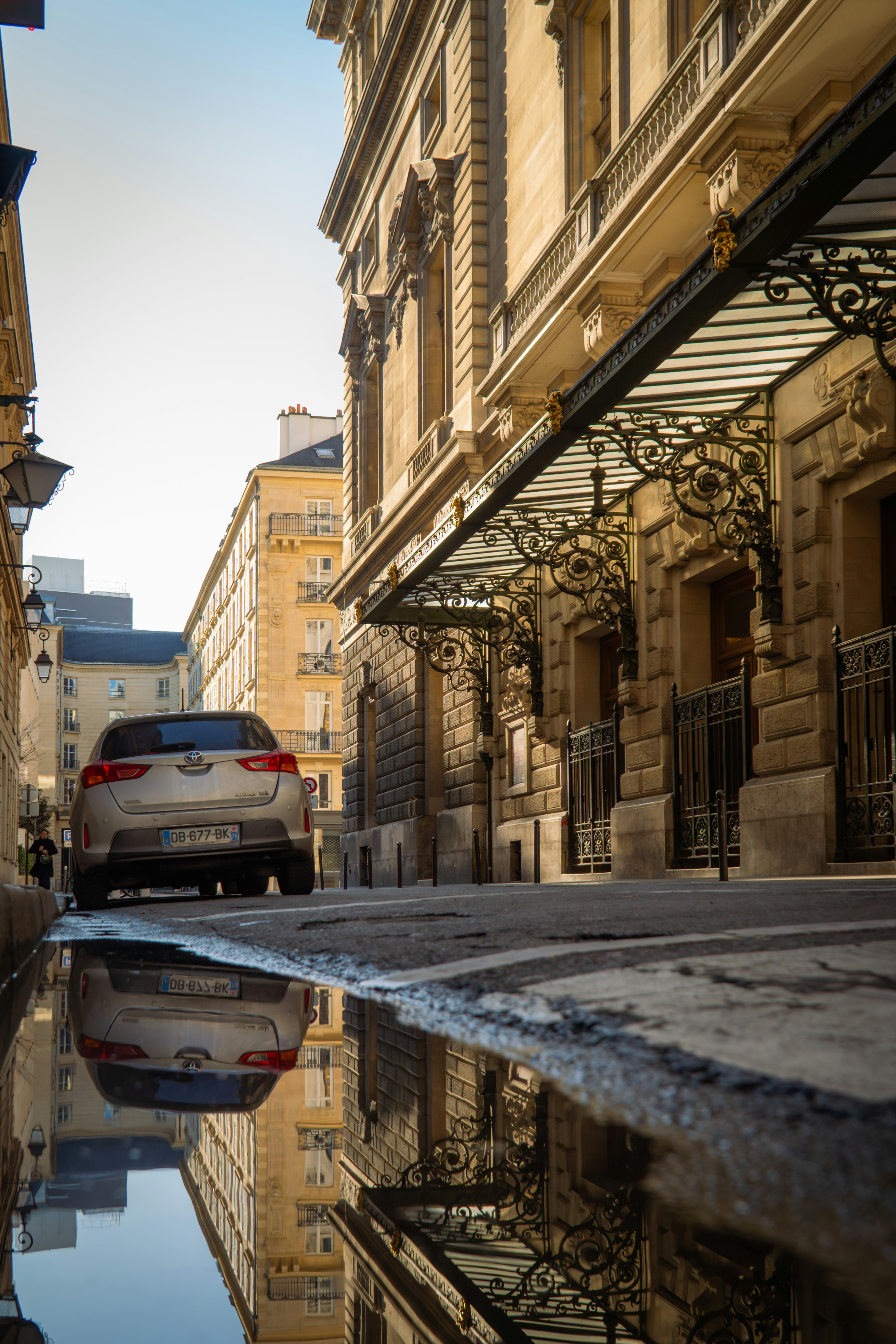 Reflected street: a quiet car and ornate façades in perfect stillness