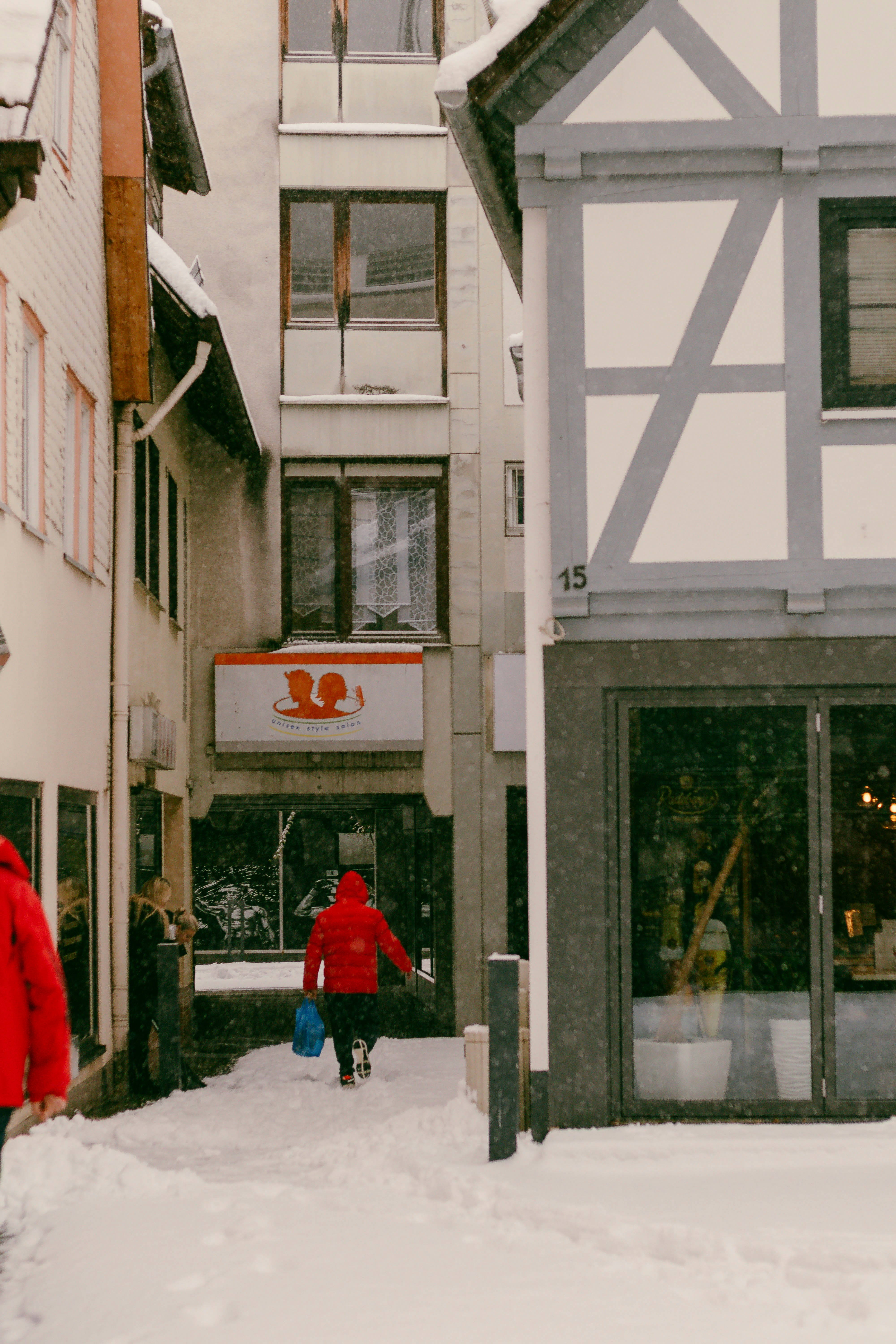 Winter Alleyways: Red Jacket Amid Snowy Shopfronts
