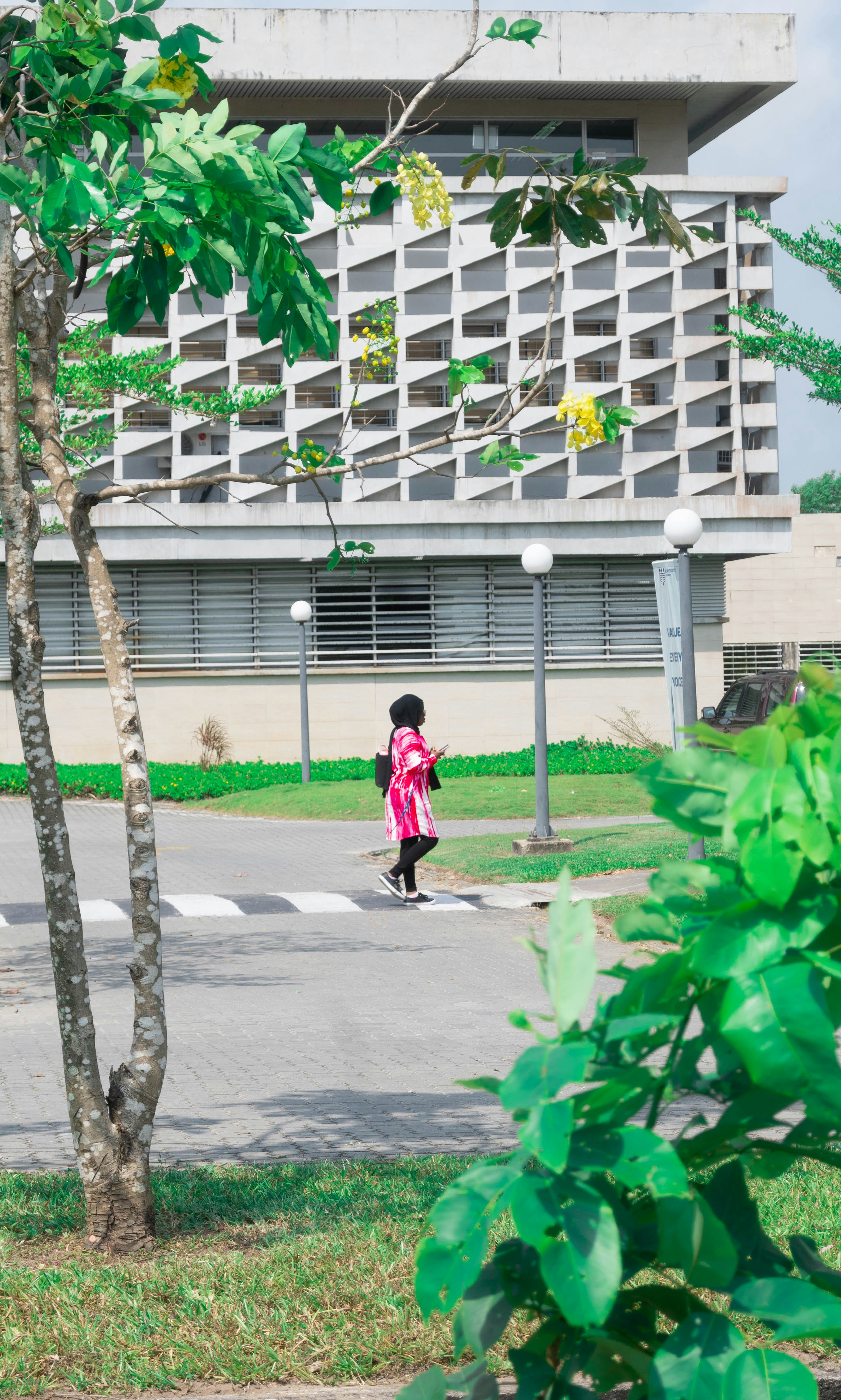 Walking Scholar in Front of a Geometric Campus Facade