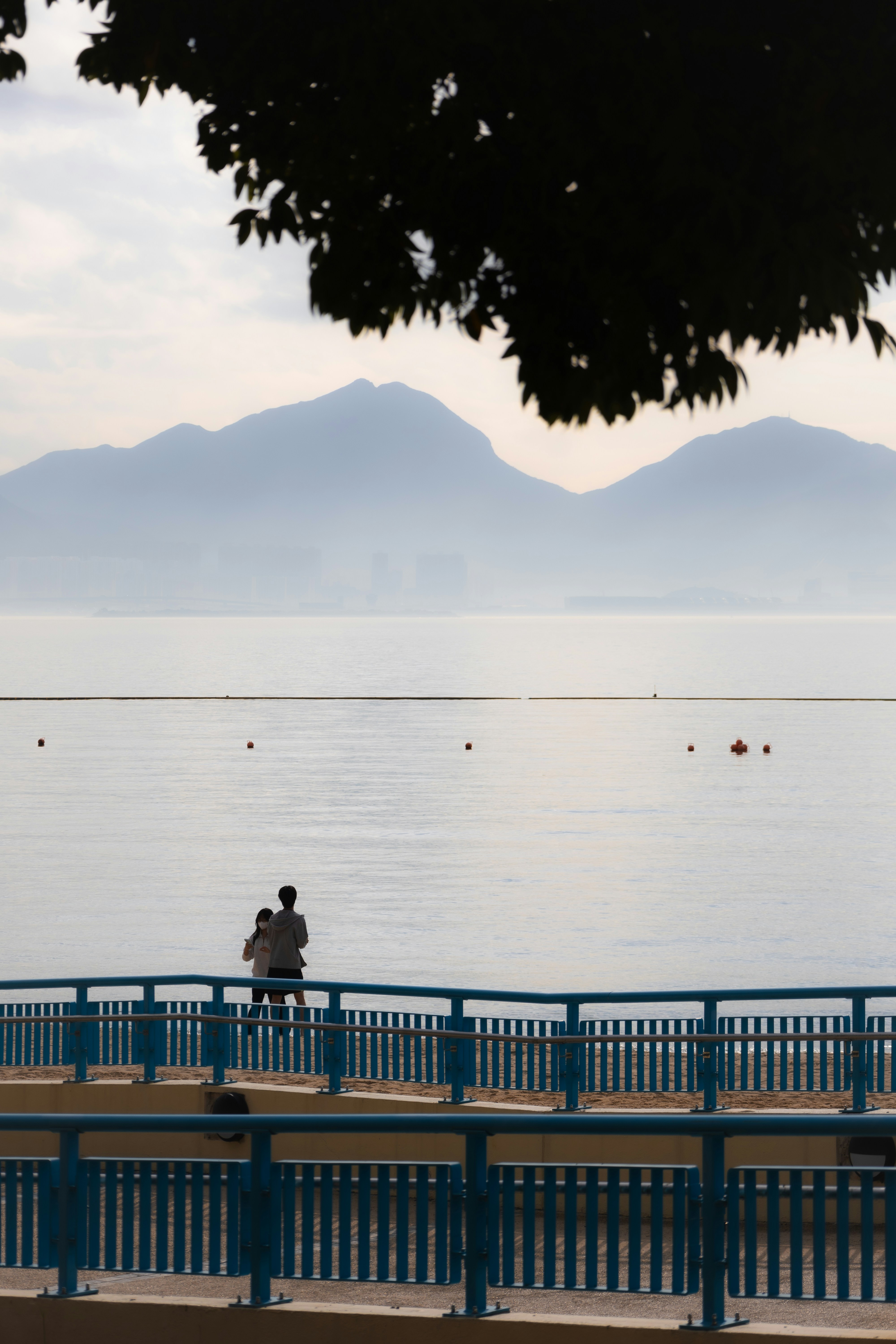 Couple by the Blue railing as Morning Mist Lifts Over Lake and Mountains