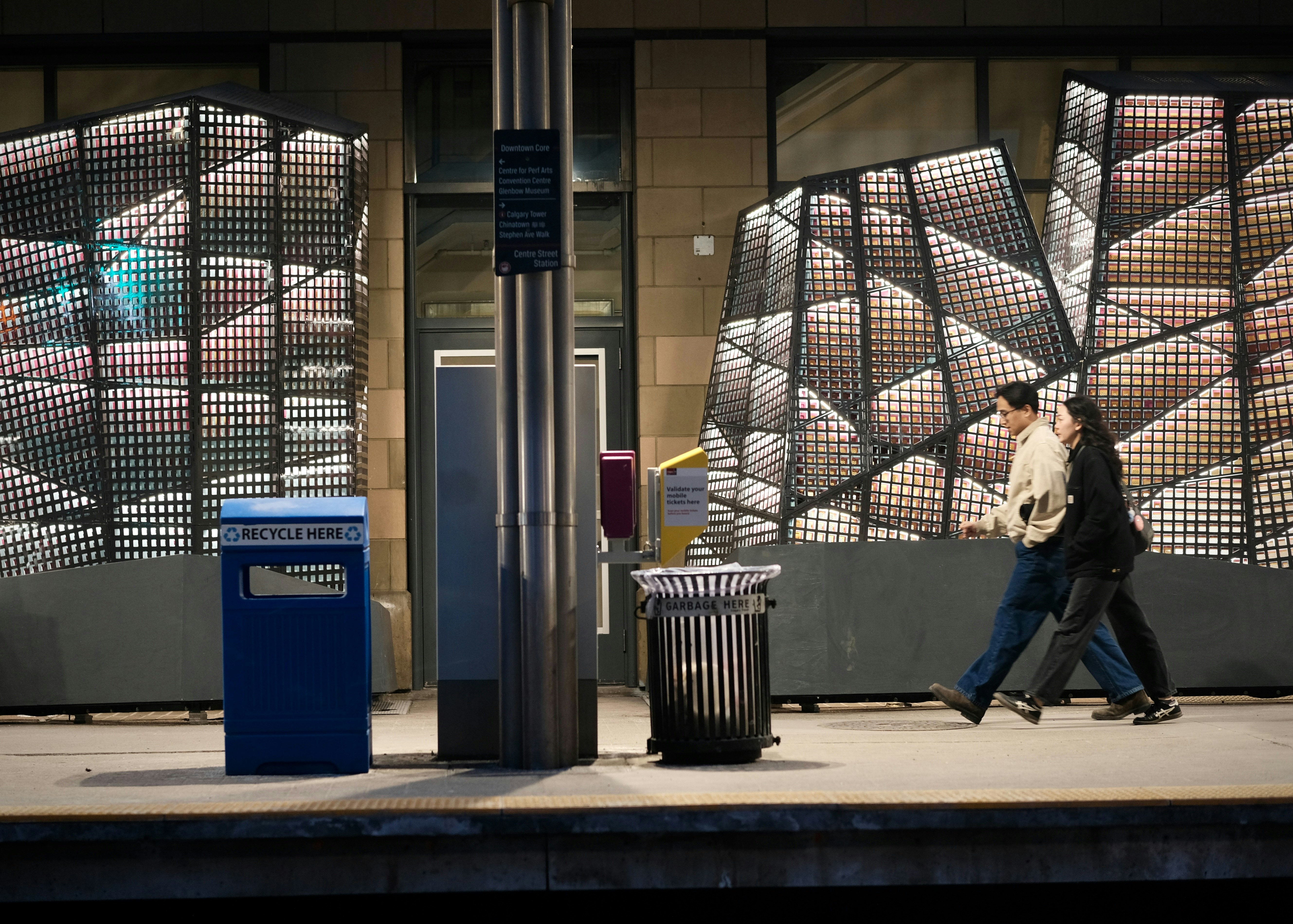 Two Passersby in a Fragmented Glass Pavilion