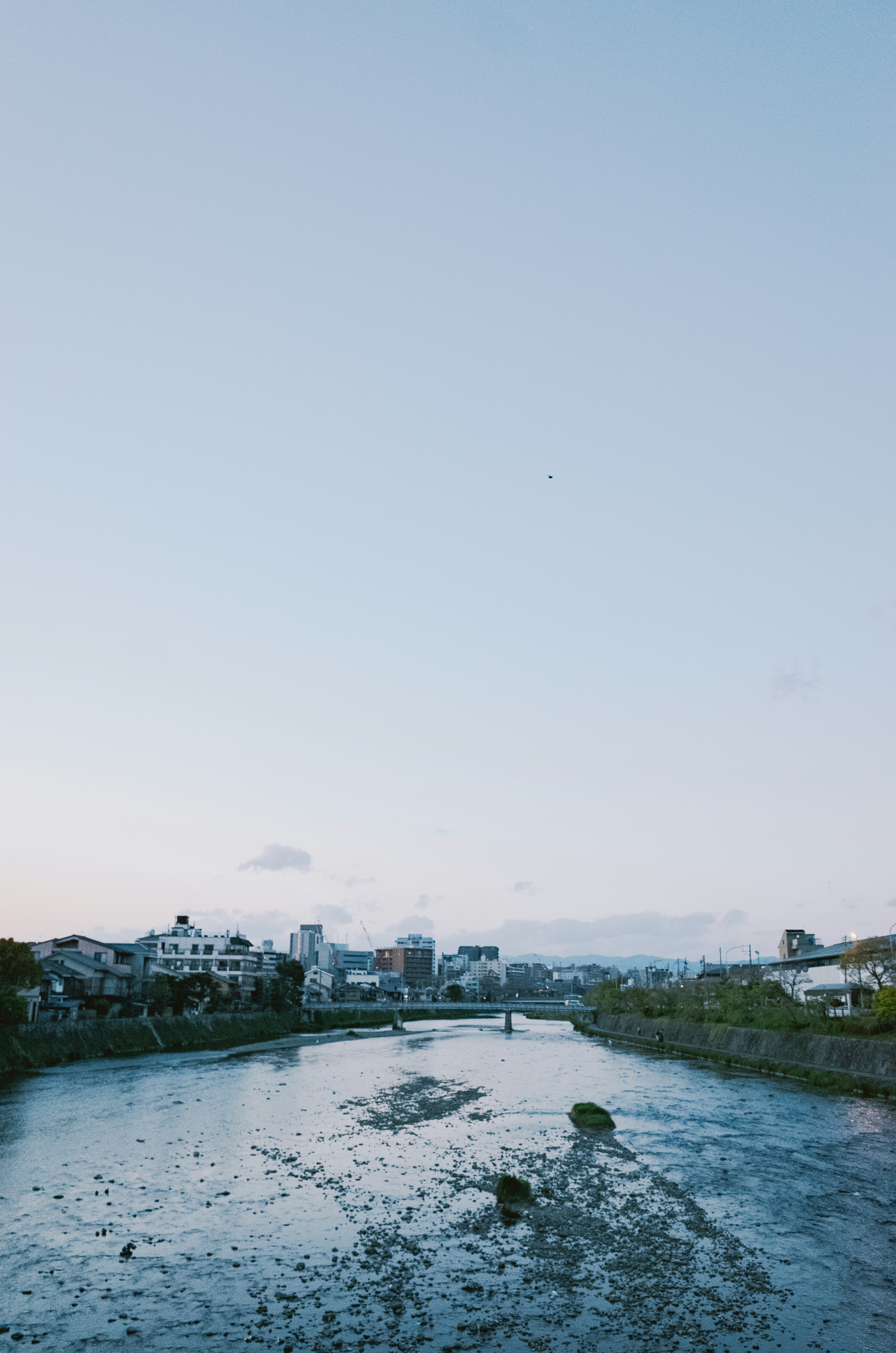 Riverline at Dusk: Cityscape Reflections under an Expansive Sky