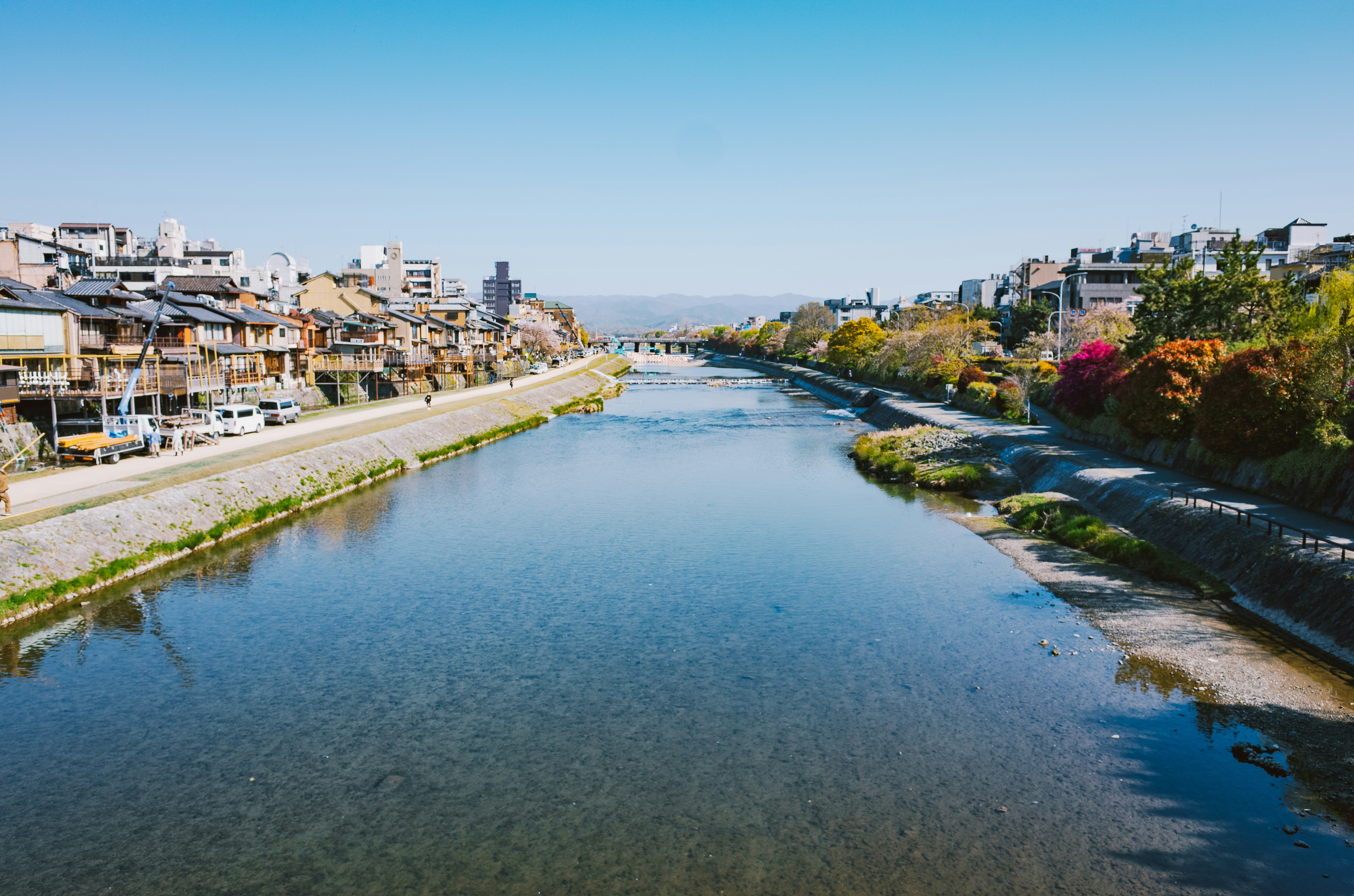 River avenue: Kyoto-like canal flanked by houses under a bright noon sky