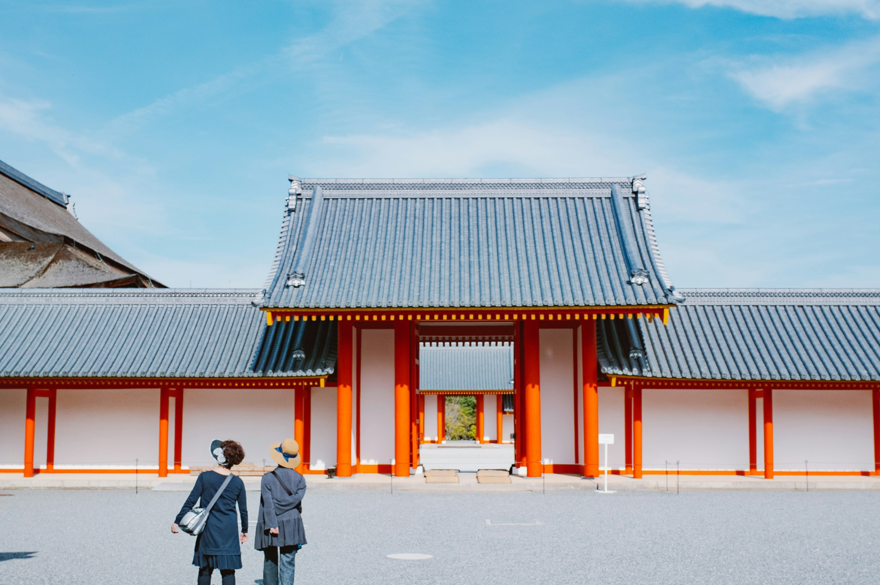 Gate to Quiet Grandeur: Travelers Approach a Red-Portalled Shrine