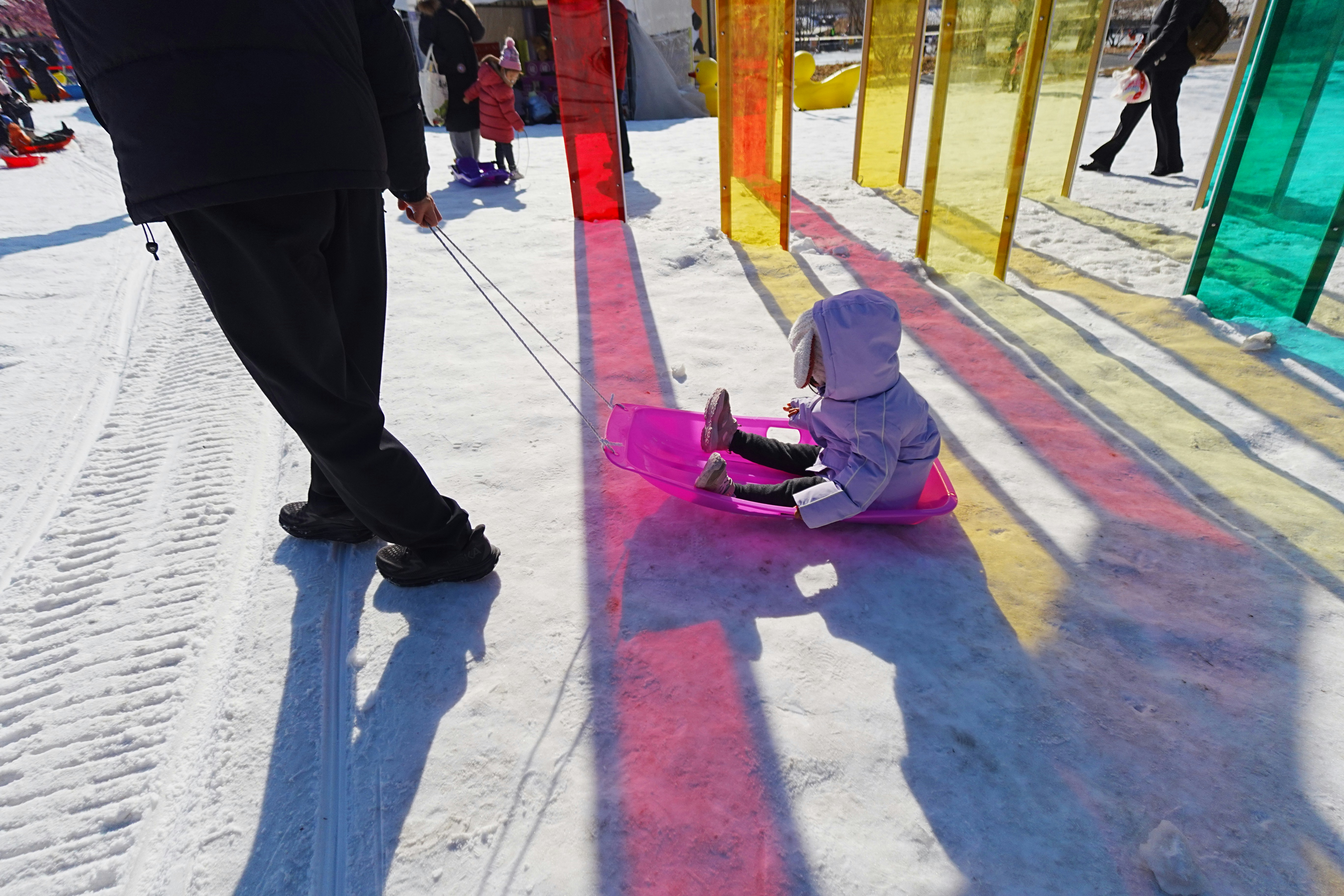 Child sledding in snow with colorful panels