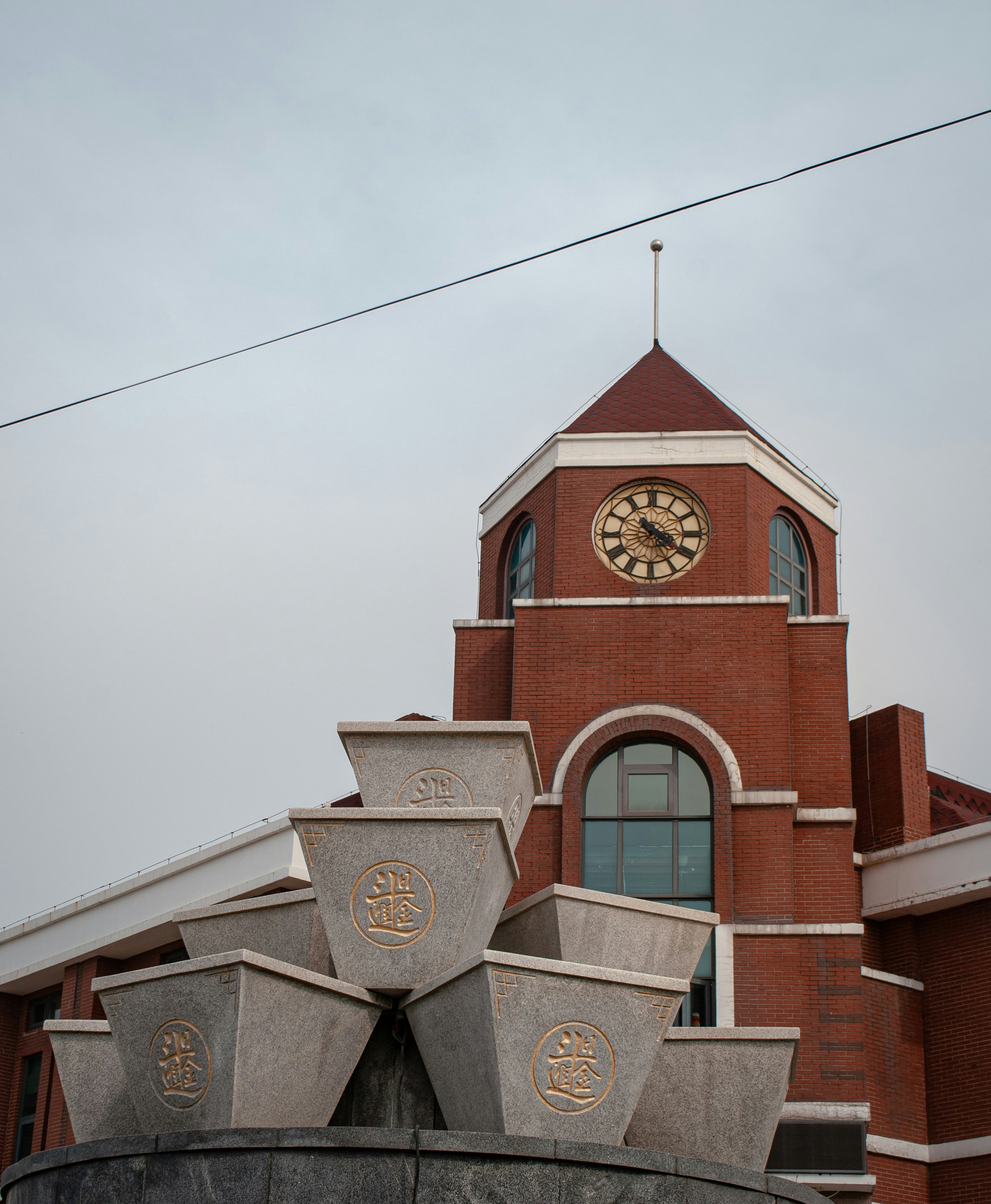 Clocktower Over Courtyard: A Red Brick Facade and Geometric Stone Sculpture