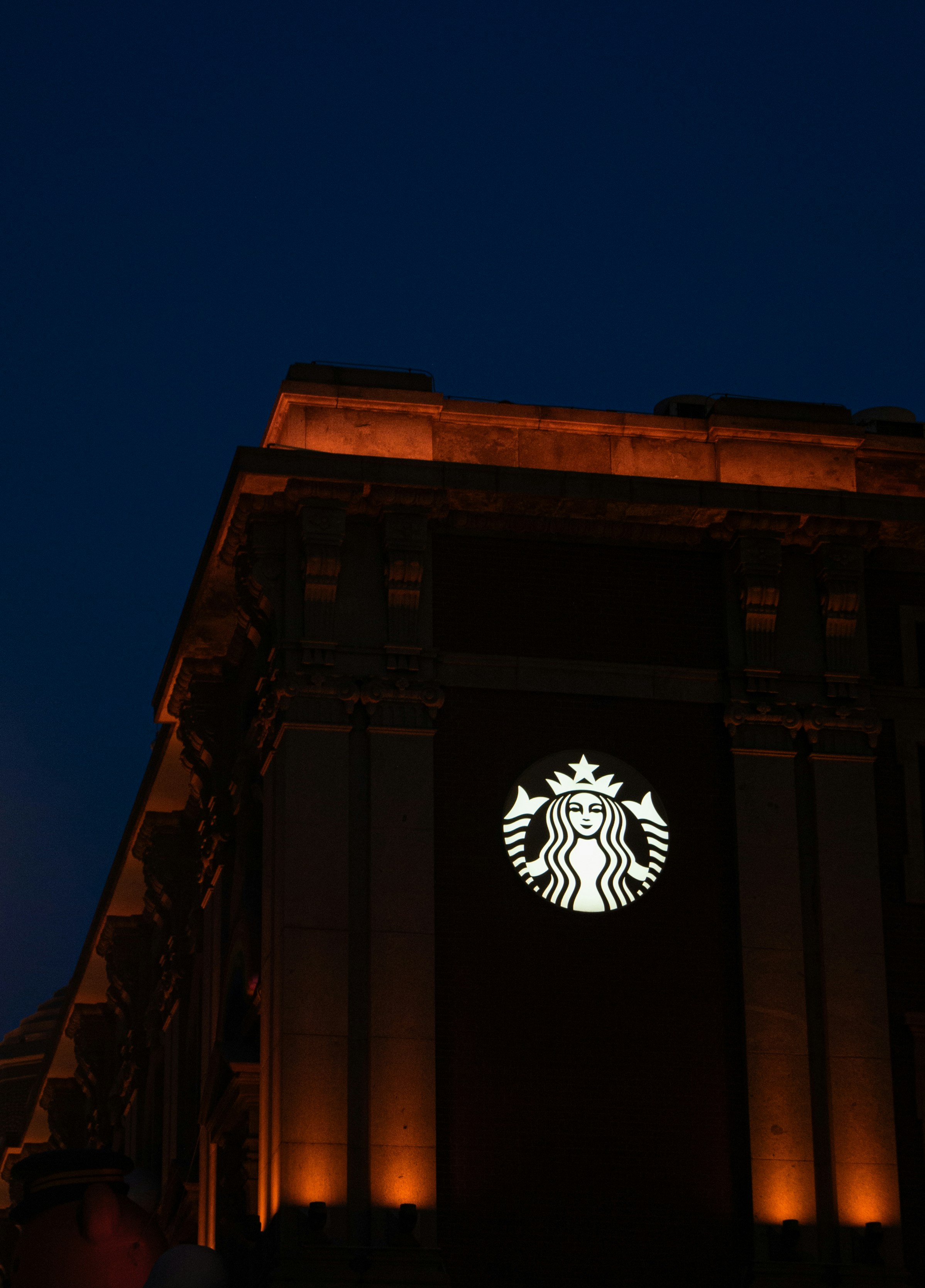Starbucks at Dusk: Illuminated Crest on Classical Facade