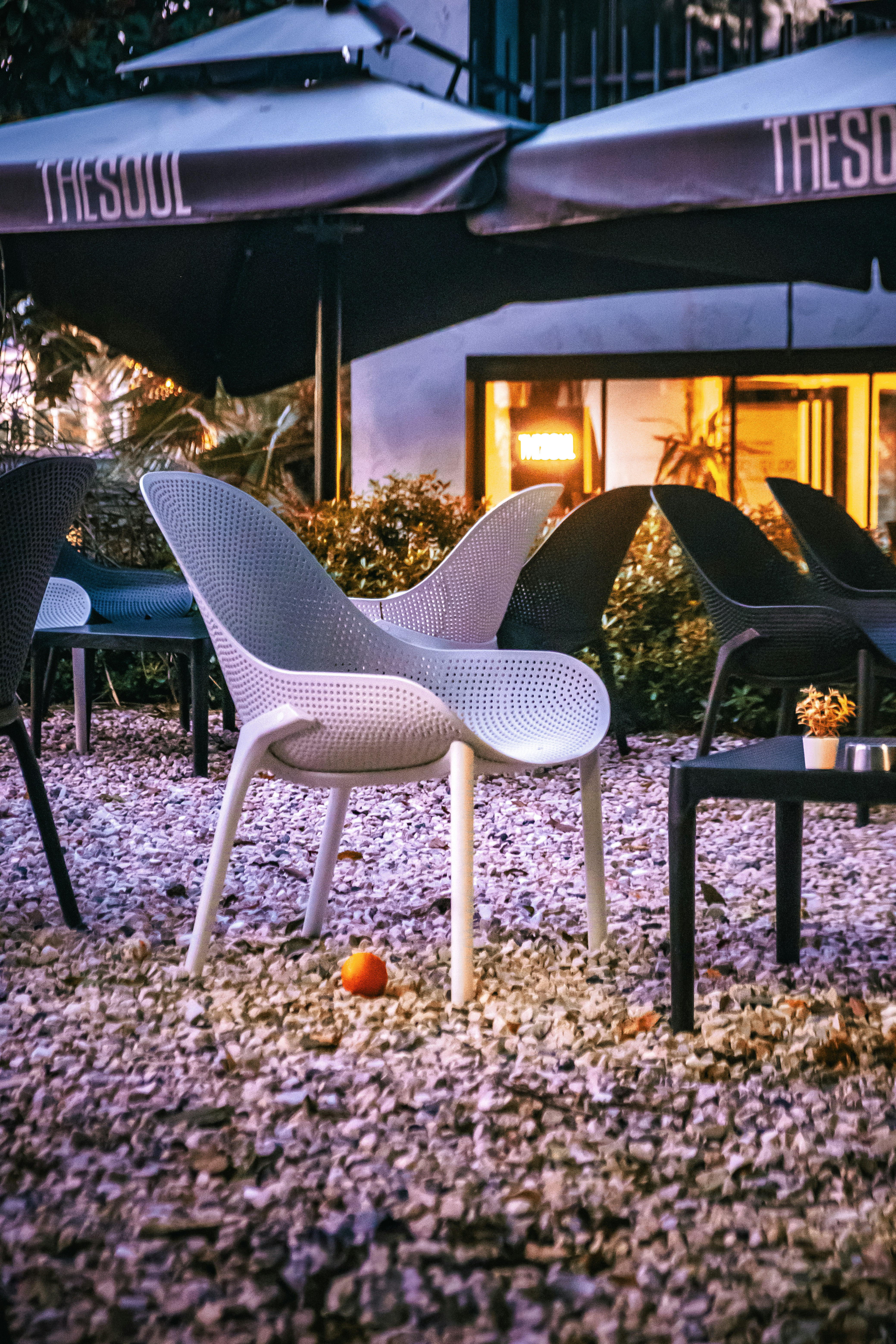 White perforated chair centerpiece under cafe umbrellas at dusk