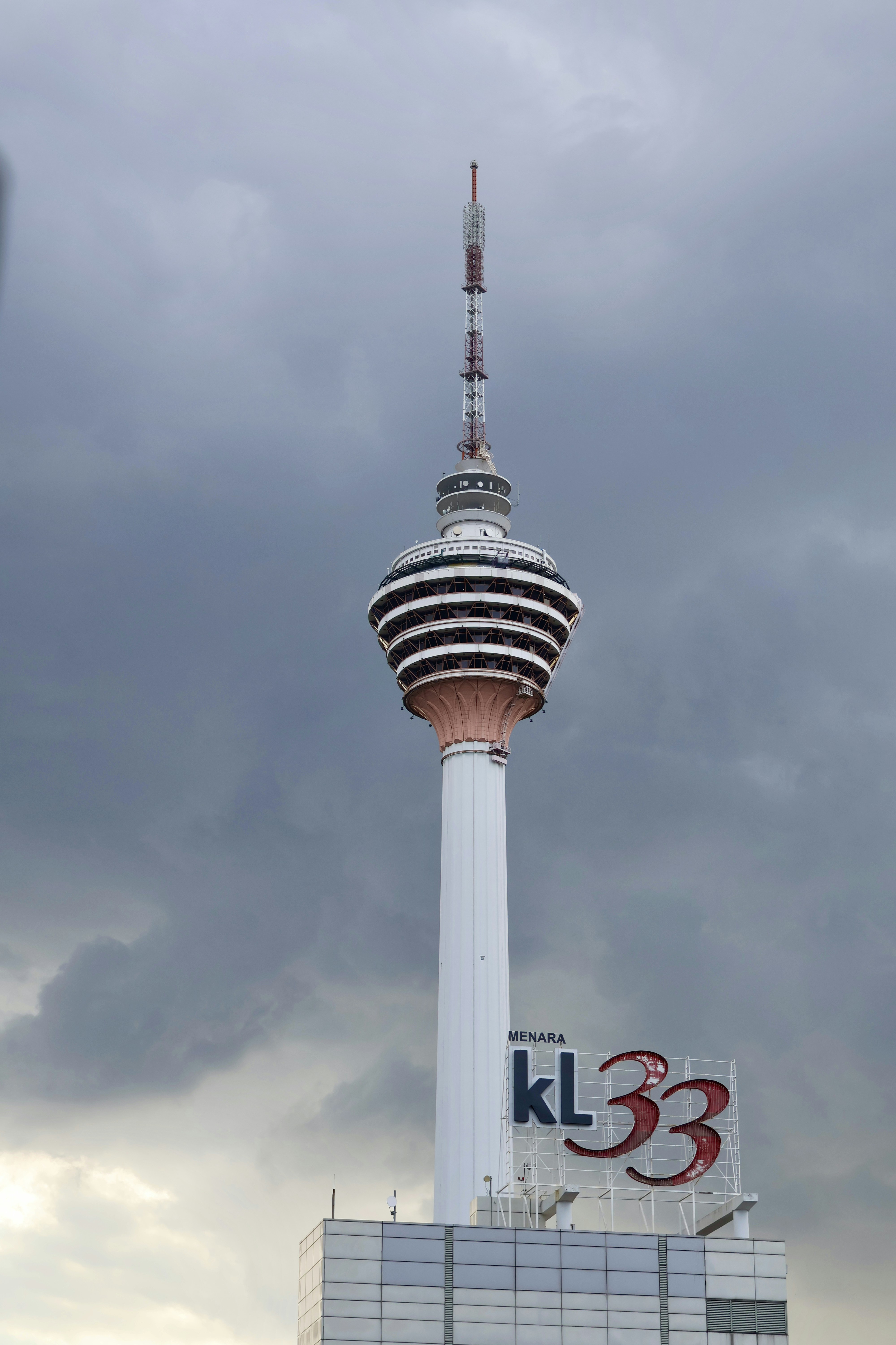 KL Tower in stormy skies: a vertical beacon crowned by bold logo