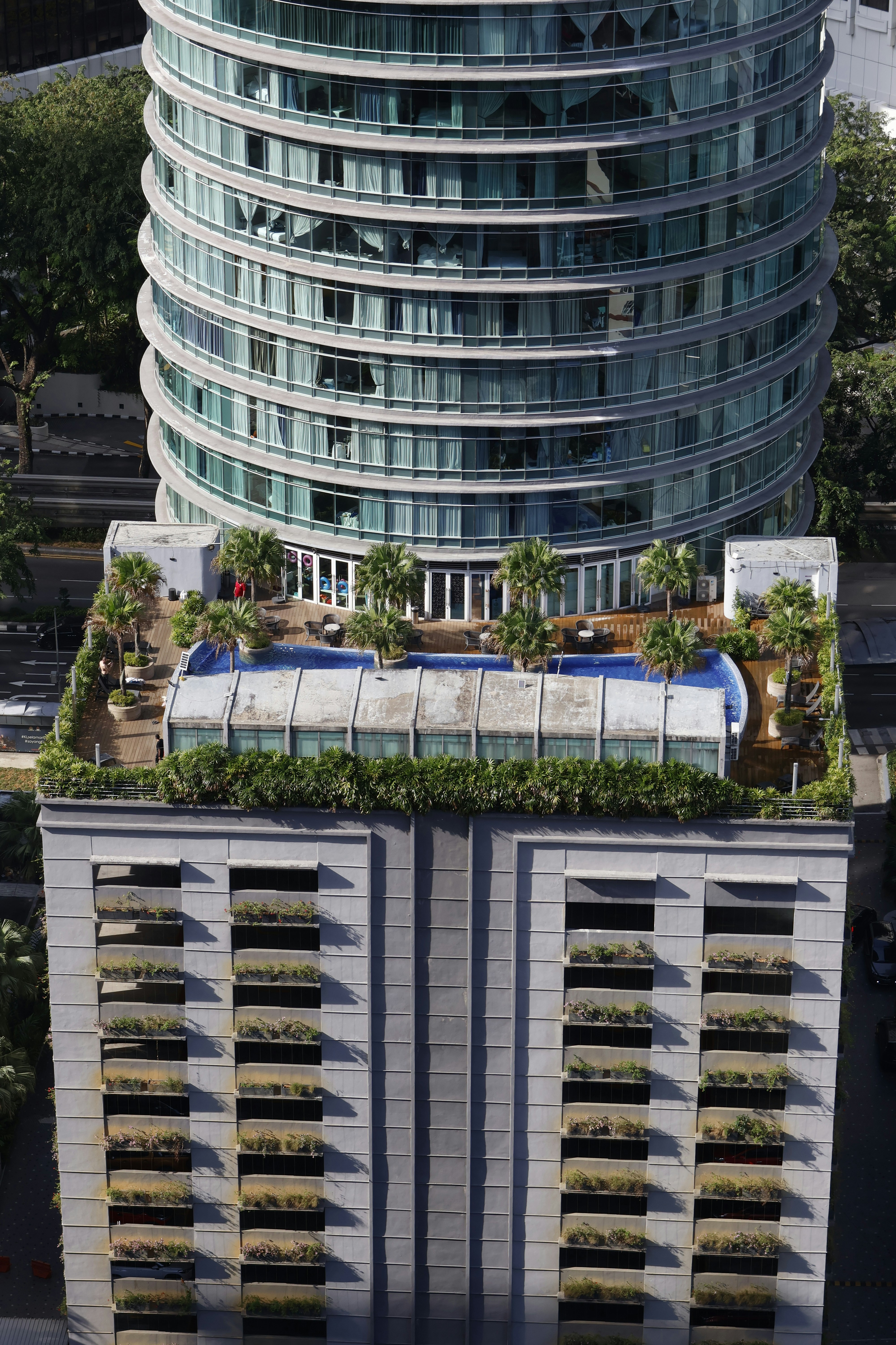 Rings and Rooftop Oasis: Aerial View of a Modern Curved Tower