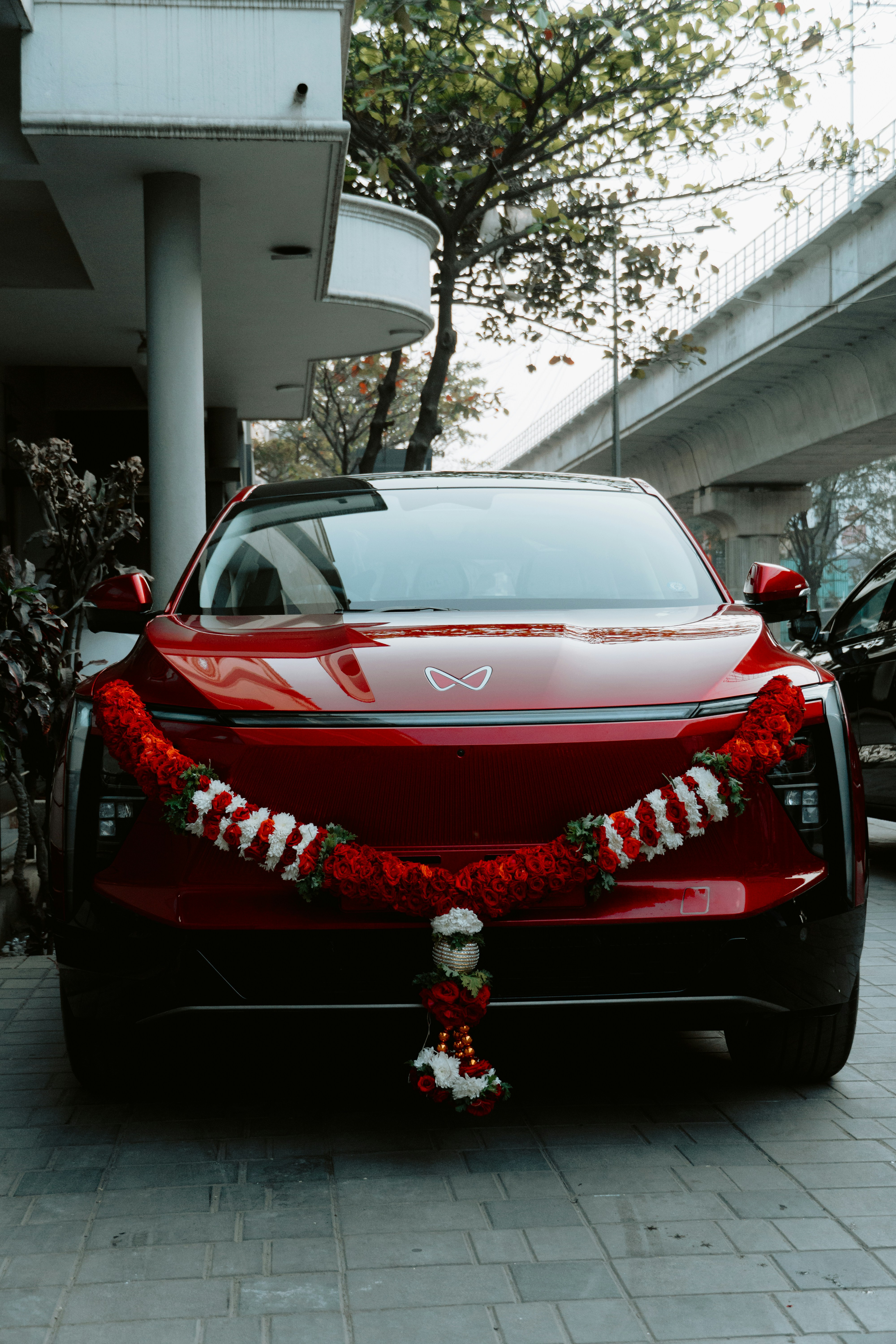 Red wedding-car with flower garland under urban canopy