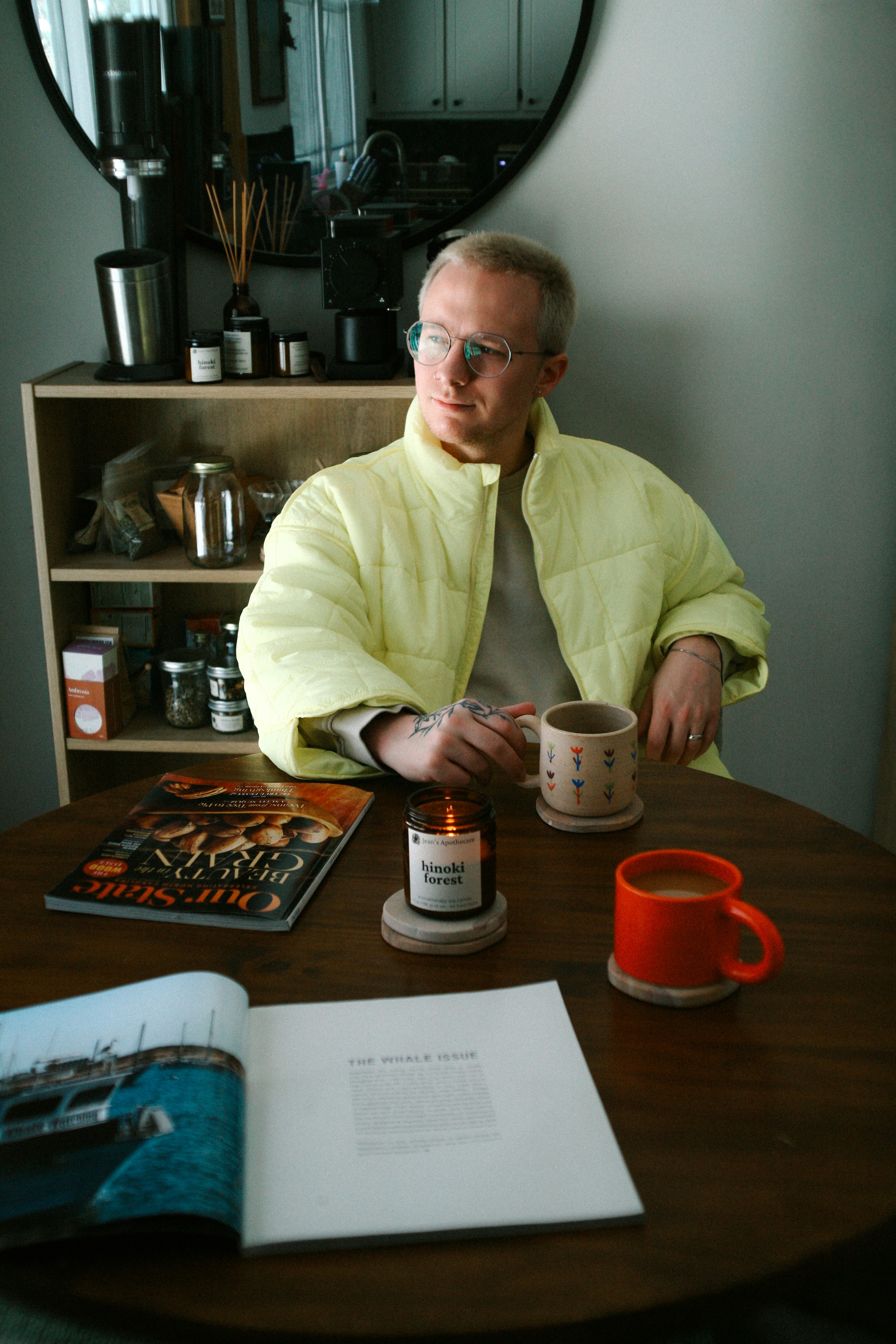 Studio Quiet: A man in a pale yellow jacket sips tea at a cluttered wood table