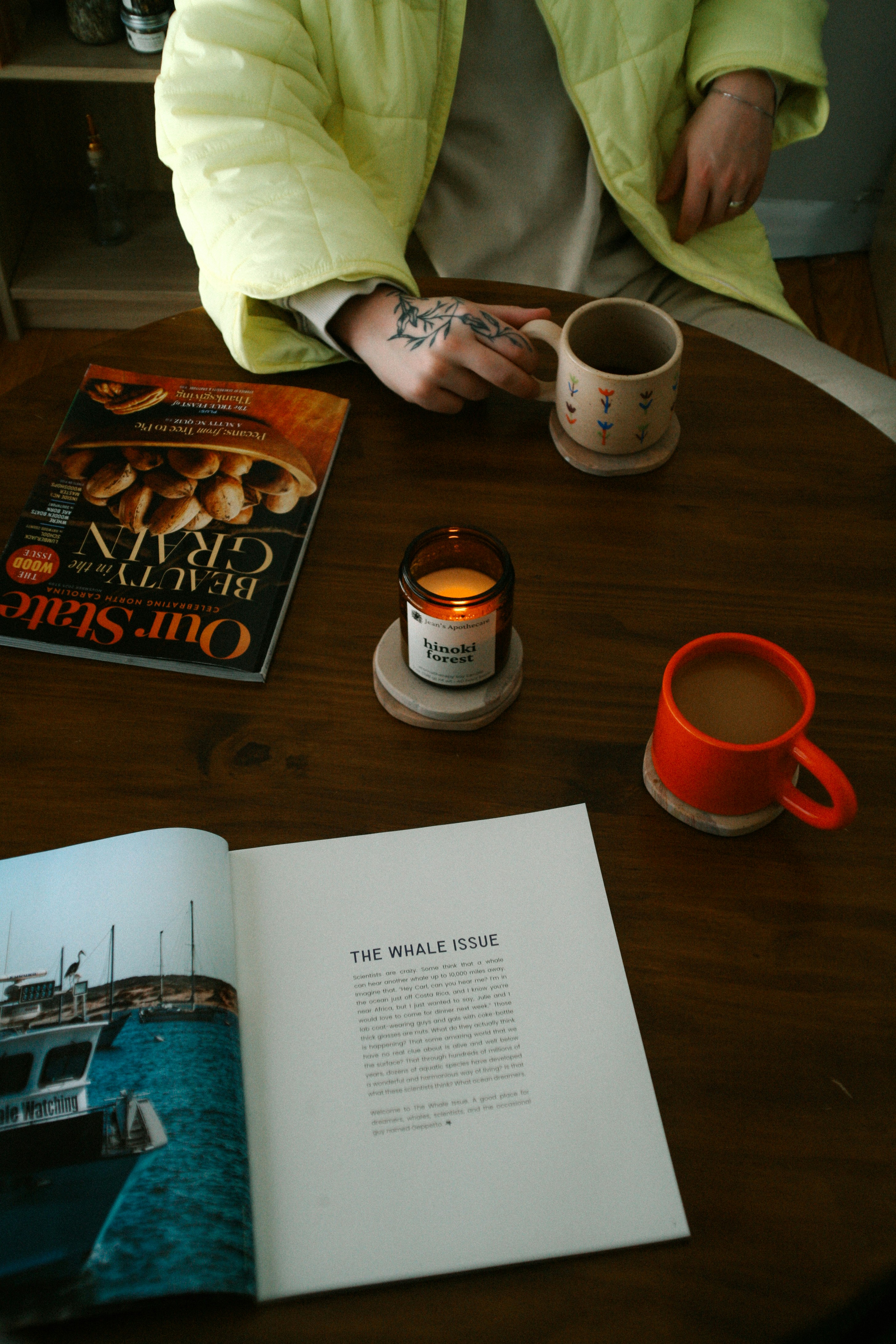 Cozy Café Quiet: Hands, Mugs, and a Magazine on a Wooden Table