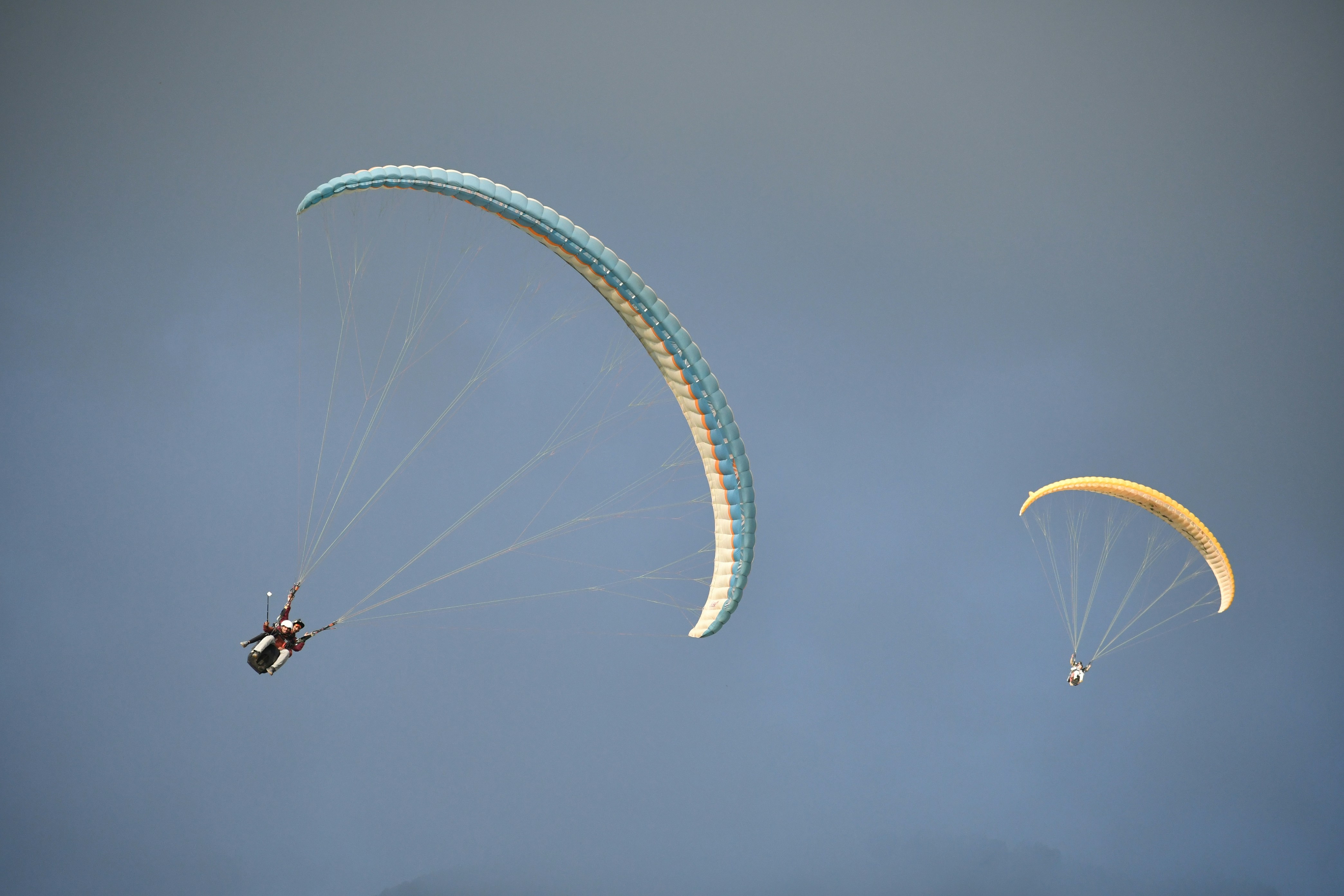 Dual Paragliders Slice the Sky: Calm Blue, Striped Wings