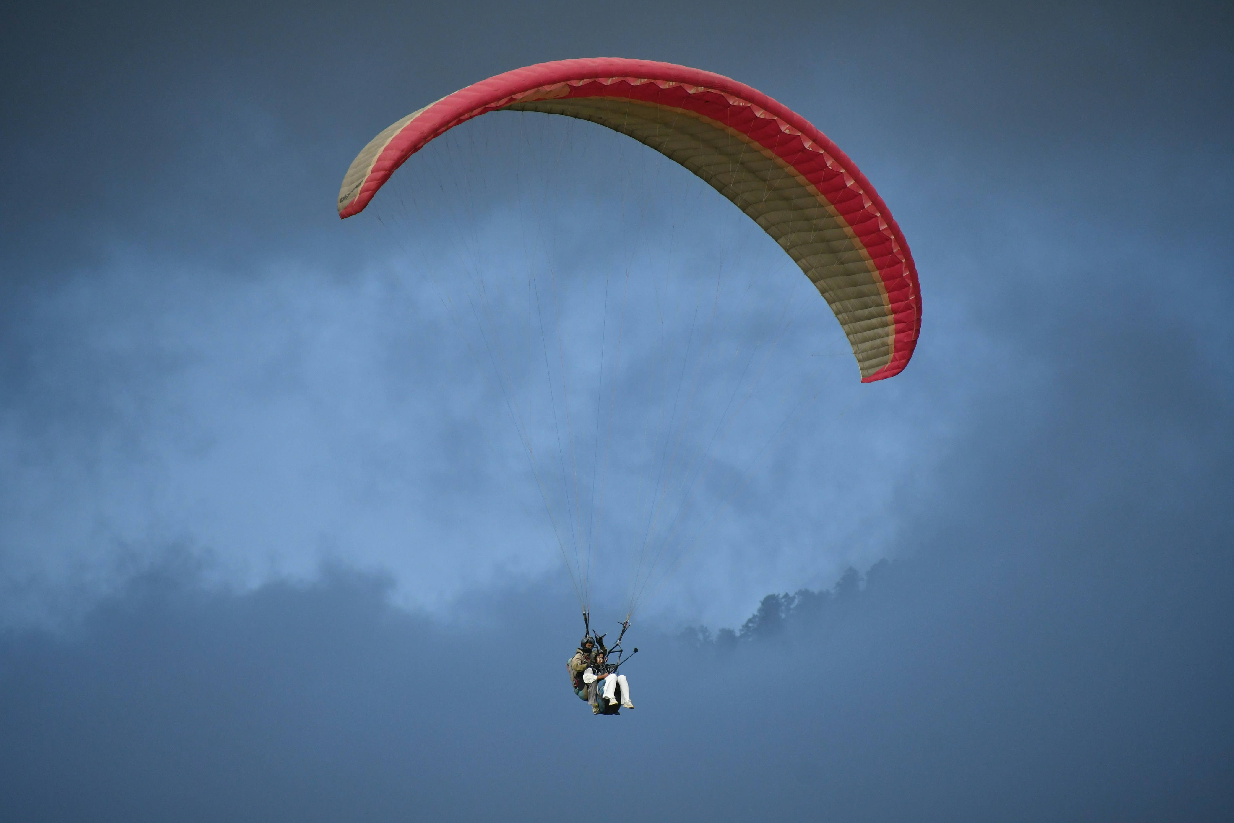 Crimson Arc: A lone paraglider rides a blue sky