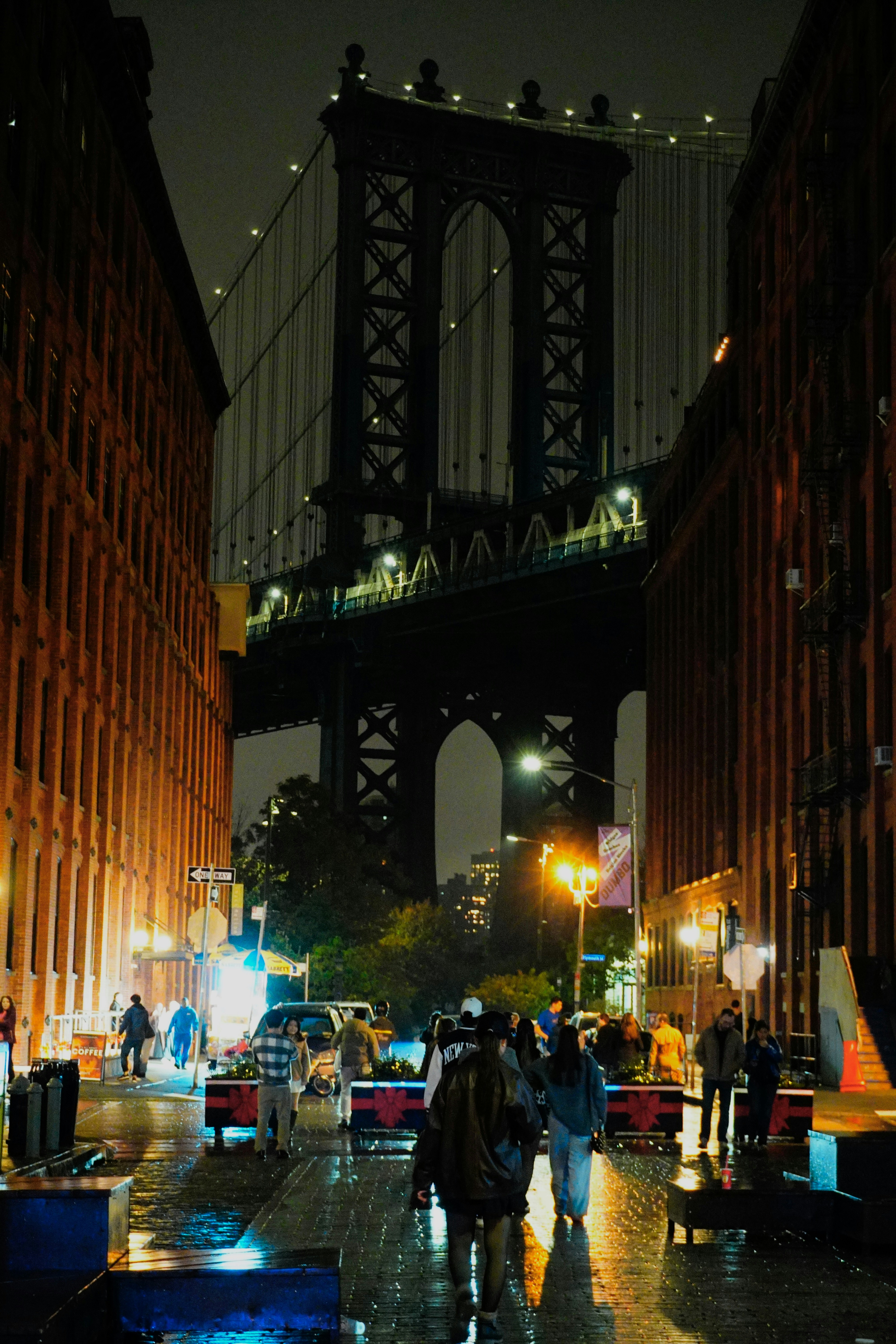 People walking down a wet street at night with bridge photo – Free Rain ...