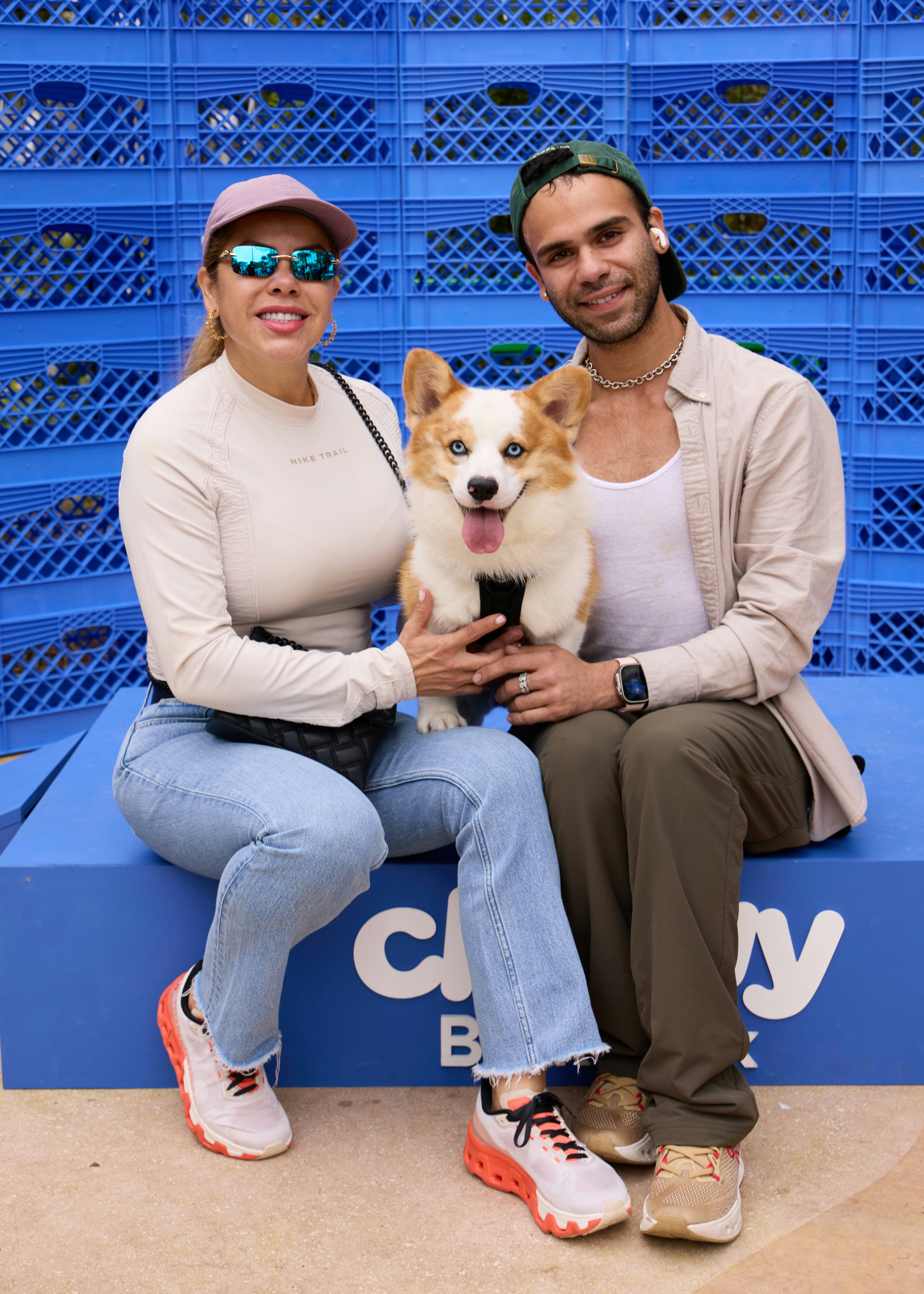 Couple and their Corgi in front of a blue crate backdrop